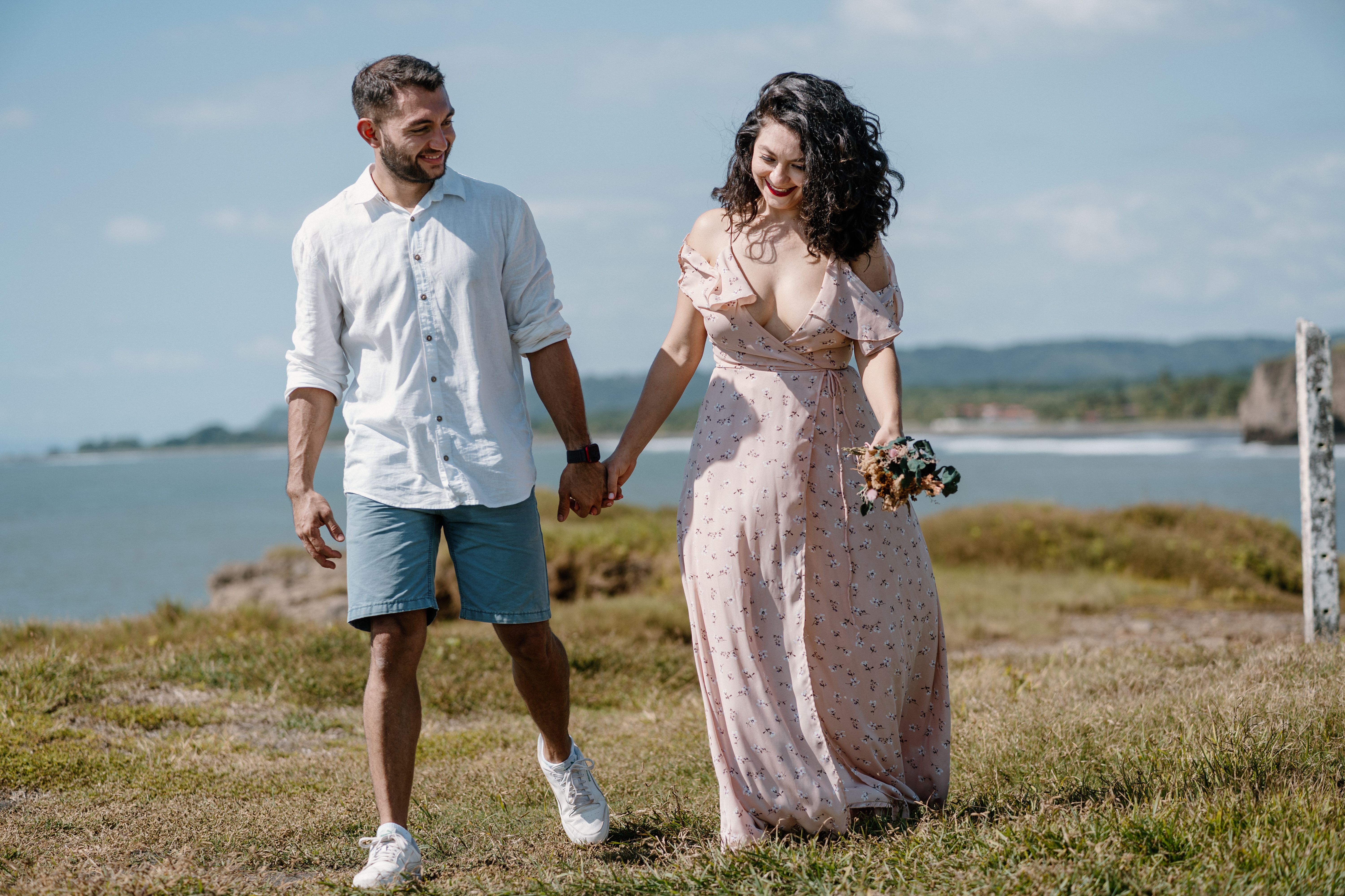 Smiling Couple Holding Hands and Walking on Coast · Free Stock Photo