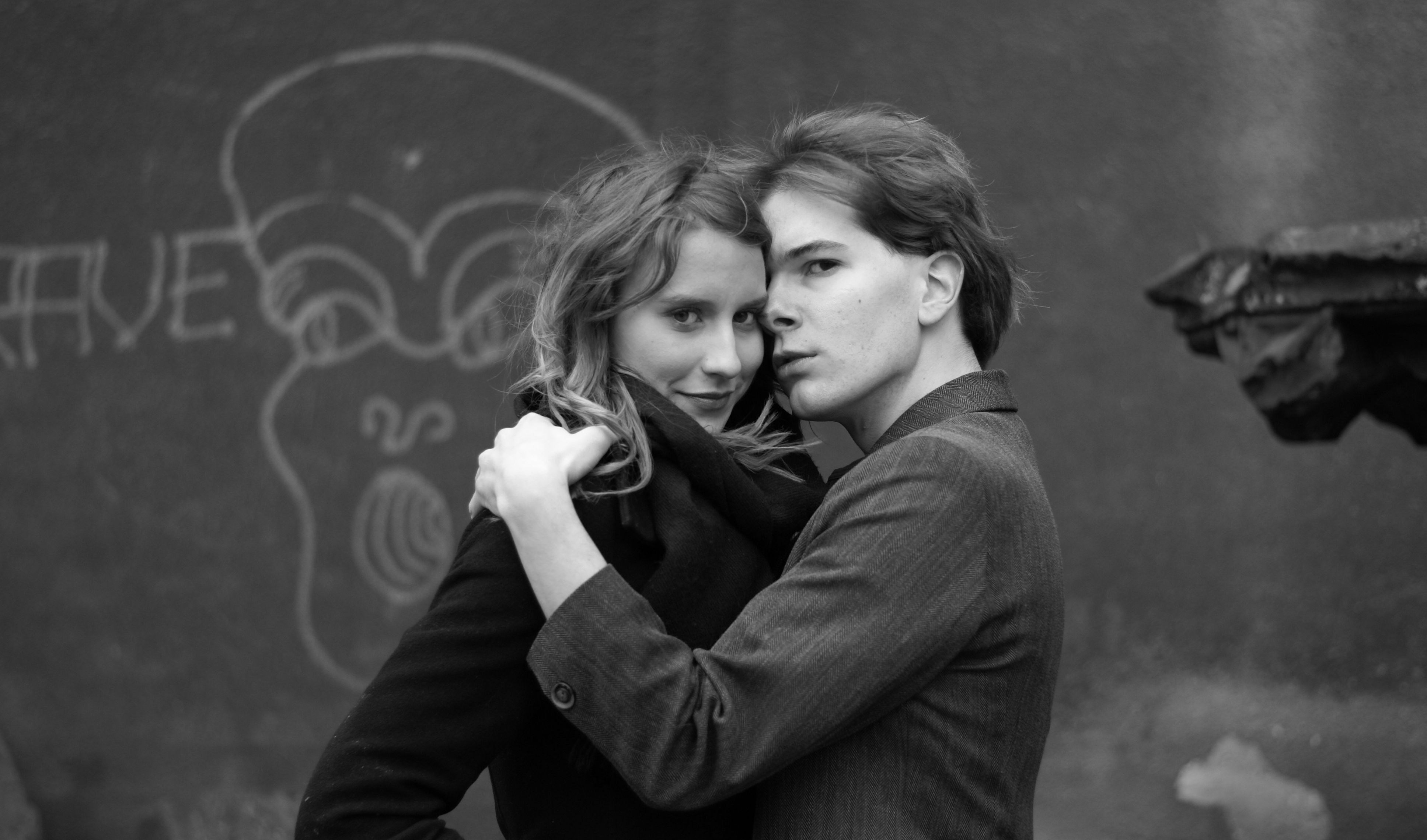 Two women hugging in front of a graffiti wall · Free Stock Photo