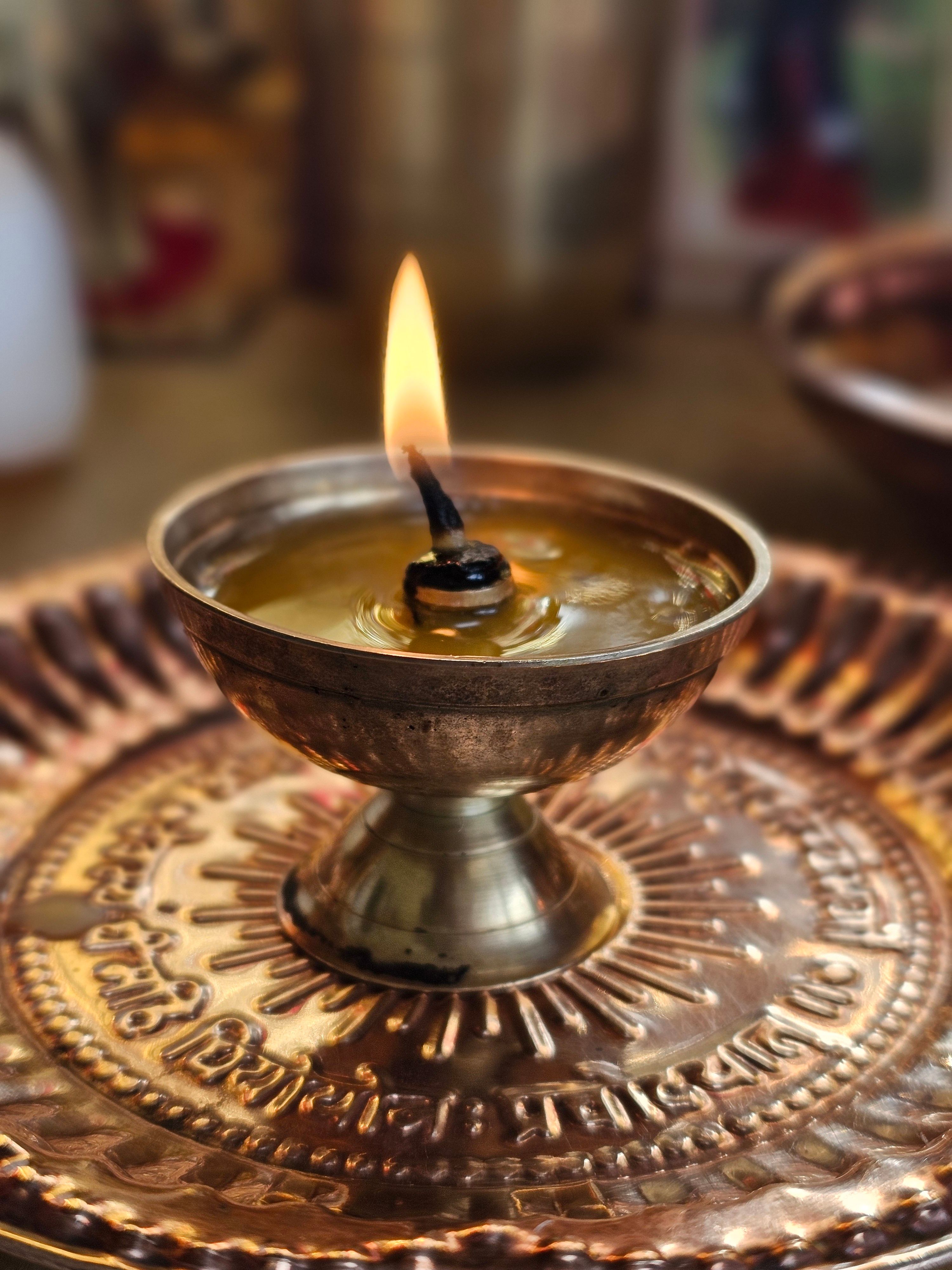 A small candle is lit on a metal plate · Free Stock Photo