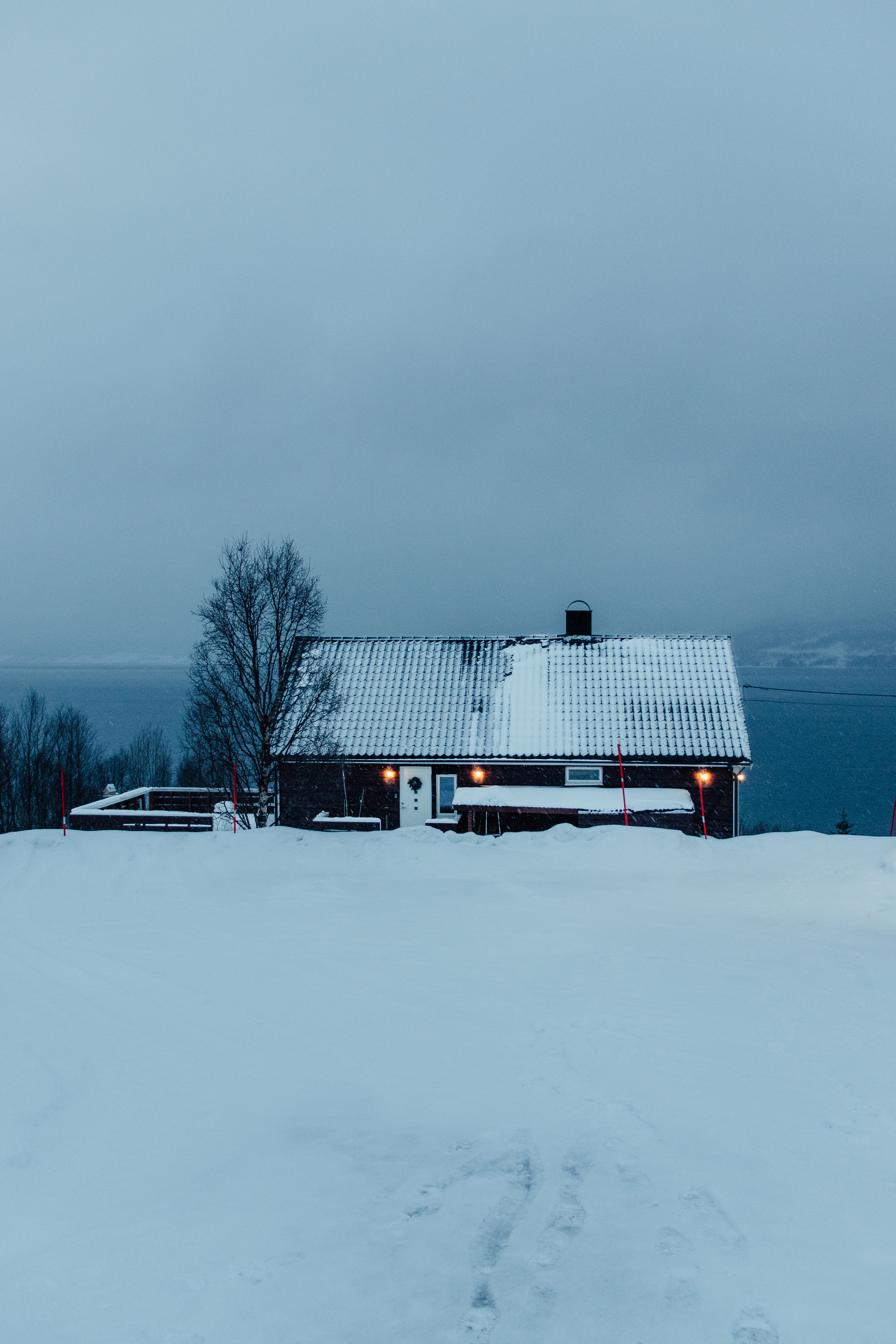 A house in the snow with a lake in the background · Free Stock Photo