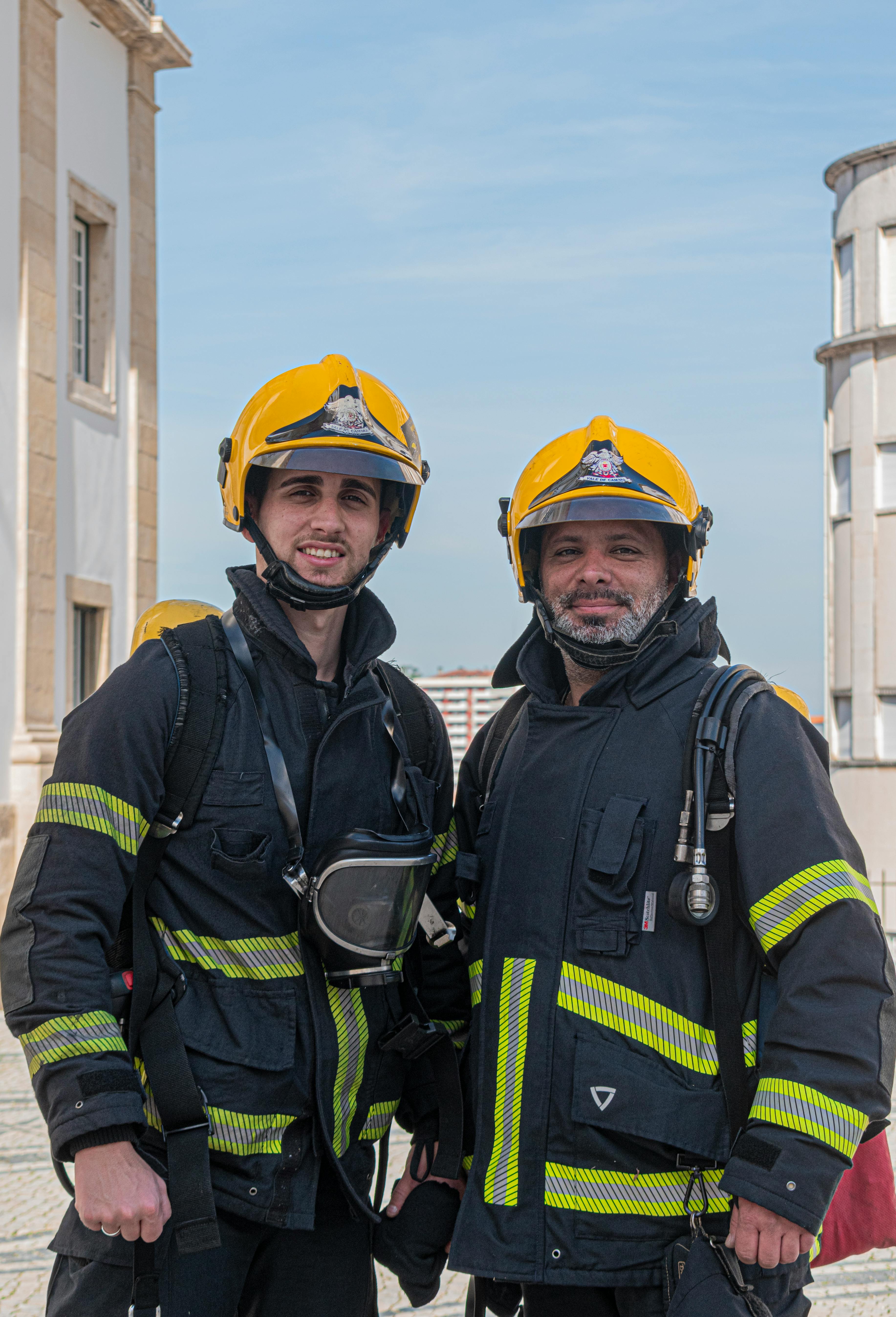Two firemen posing for a photo in front of a building · Free Stock Photo