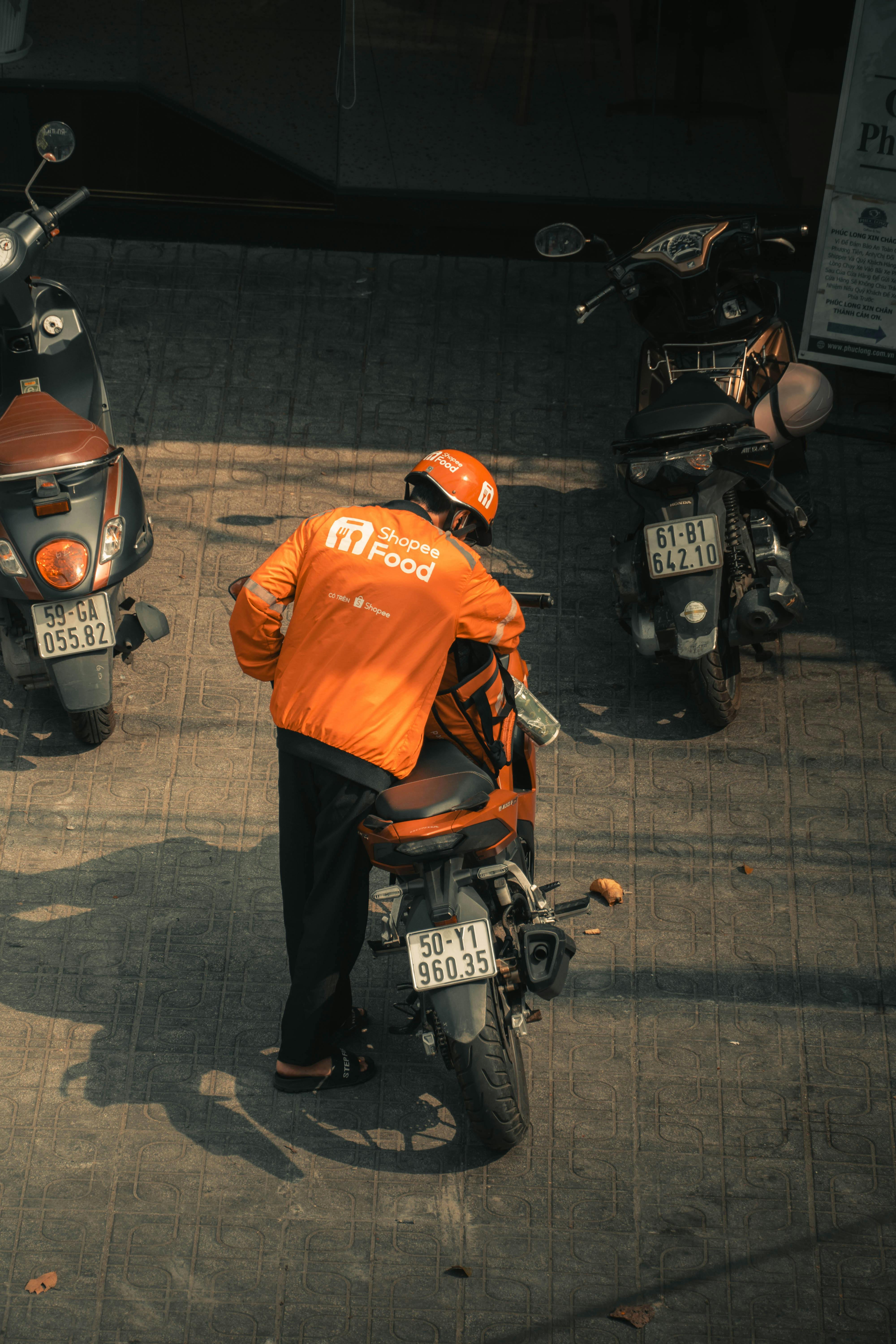 High Angle Shot of a Food Delivery Man Standing next to a Motor Scooter ... High Angle Shot of a Food Delivery Man Standing next to a Motor Scooter ...