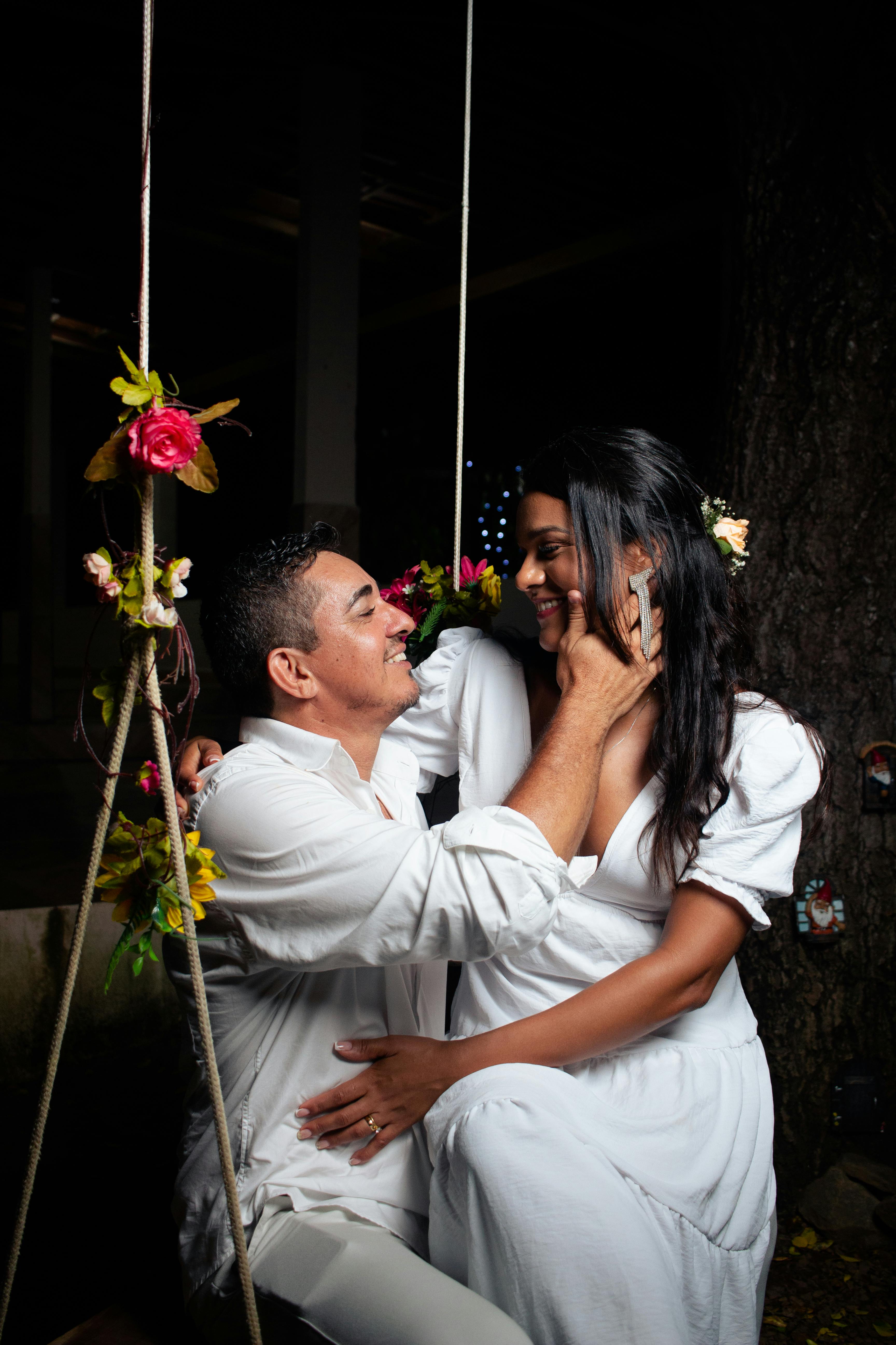 Smiling Brunette Couple in White Shirt and Dress Sitting on Swing at ...