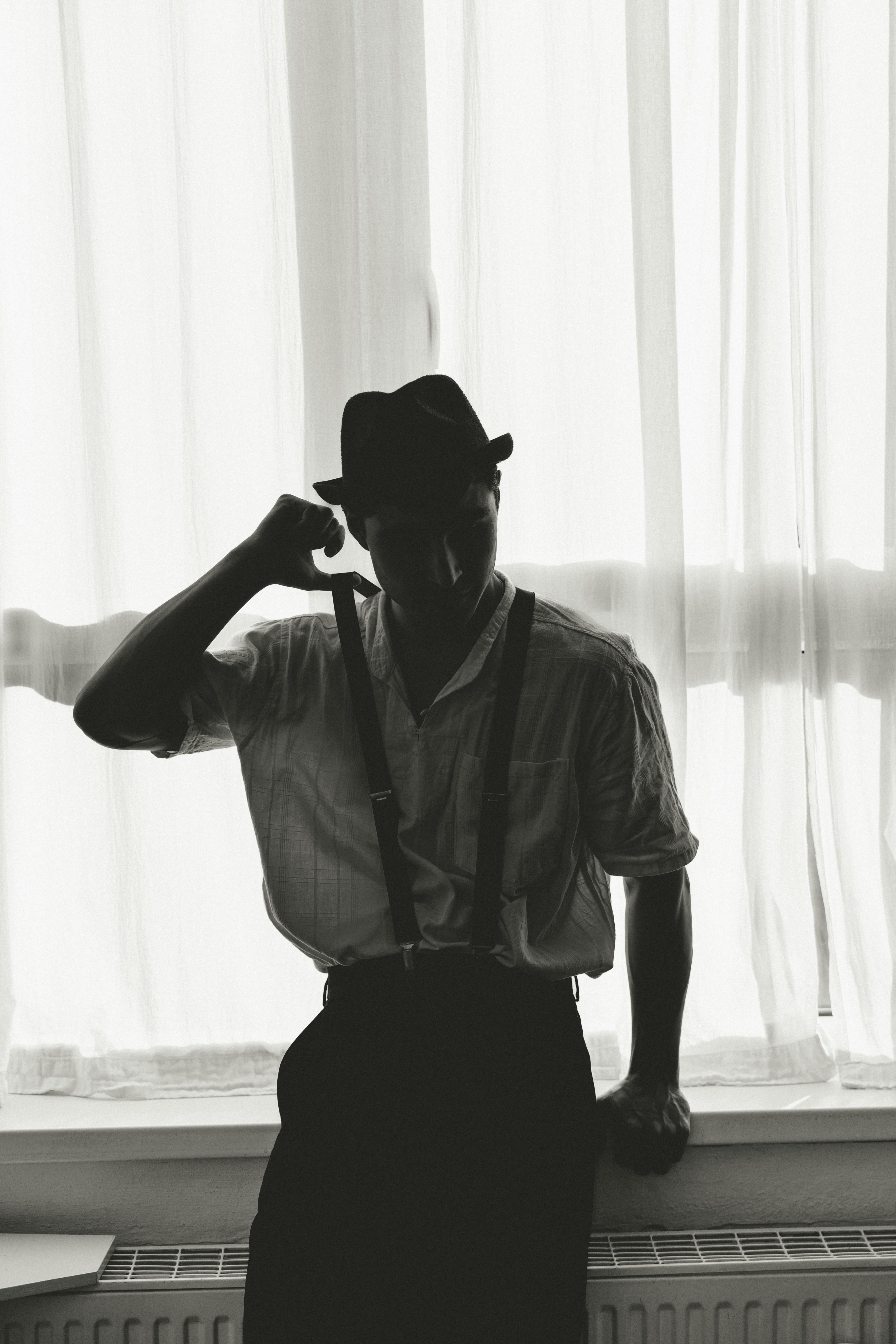 Man in Hat Fixing Suspenders · Free Stock Photo