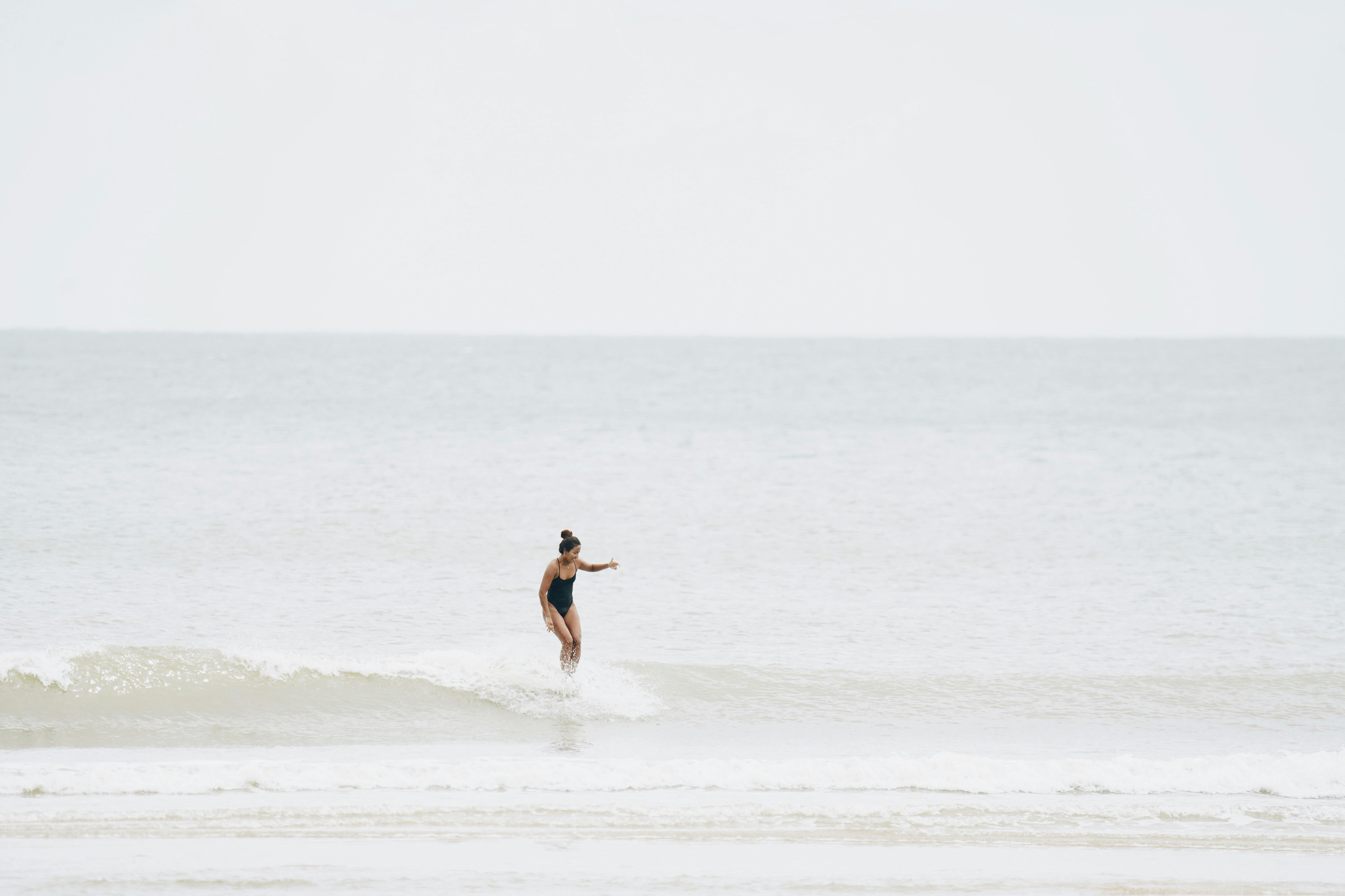Woman in Swimming Costume Surfing in Ocean · Free Stock Photo