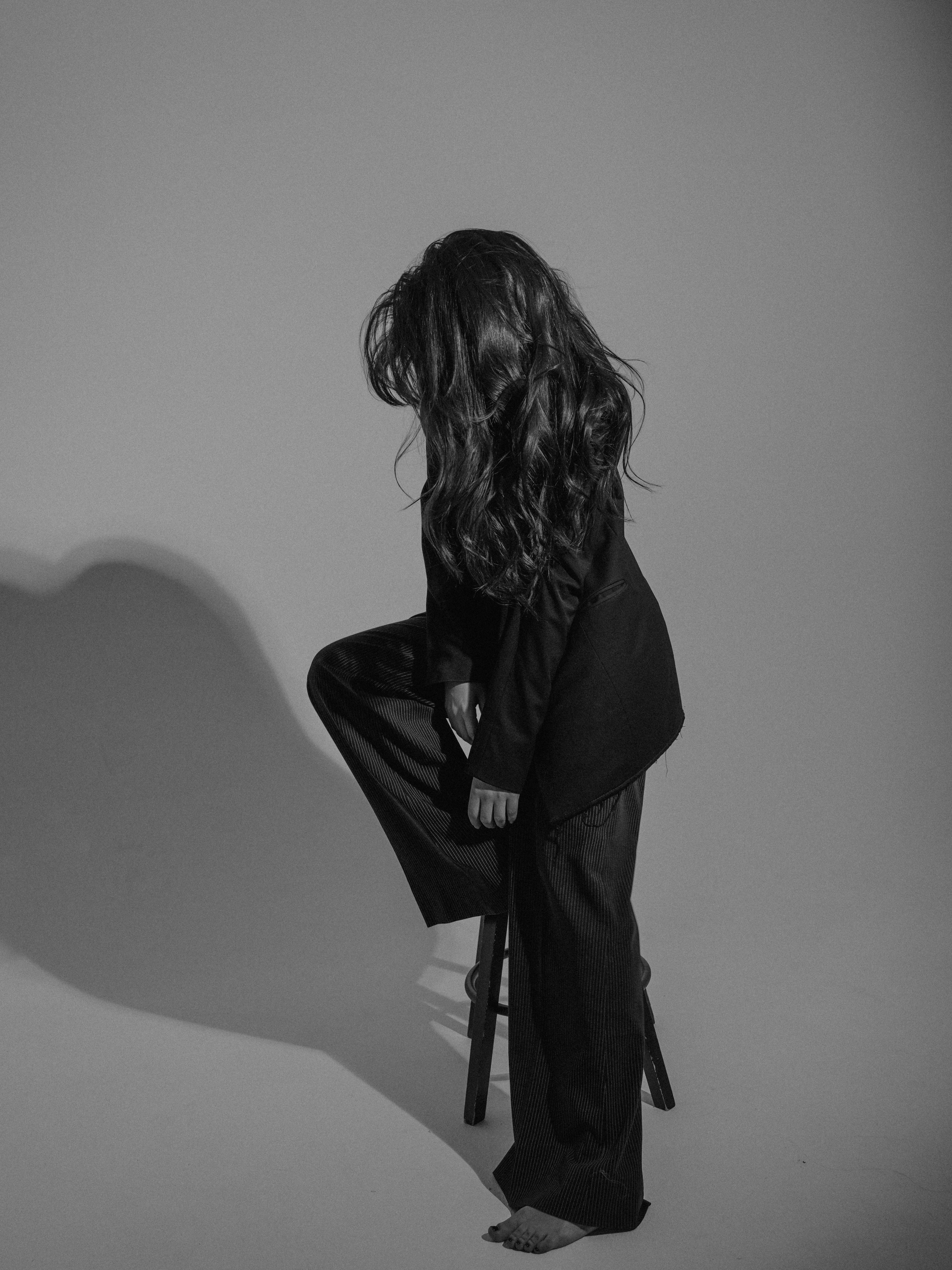 A woman sitting on a stool in a shadow · Free Stock Photo