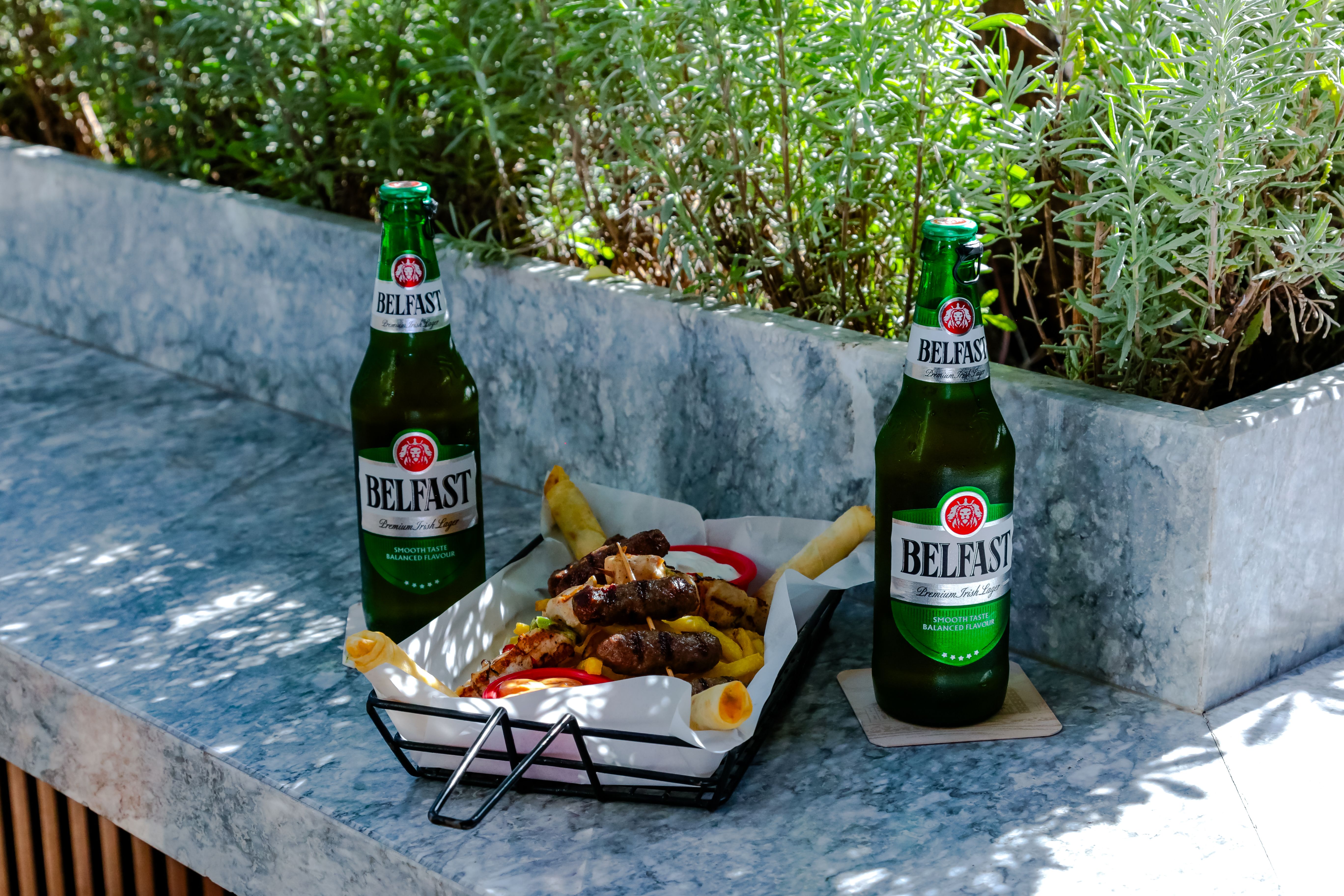 Snacks and Beer Bottles on Gray Wall in Park · Free Stock Photo