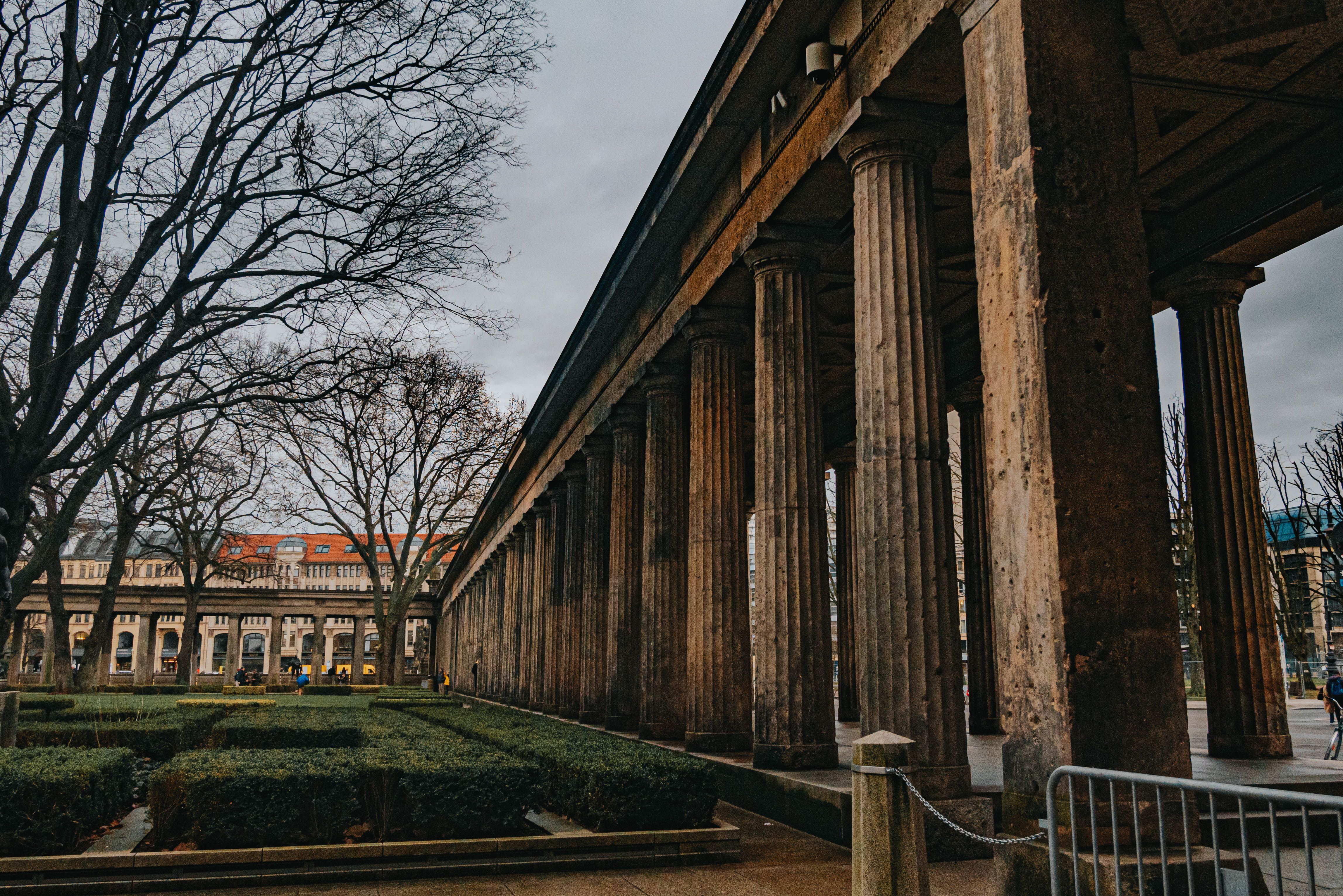 A view of a building with columns and trees · Free Stock Photo