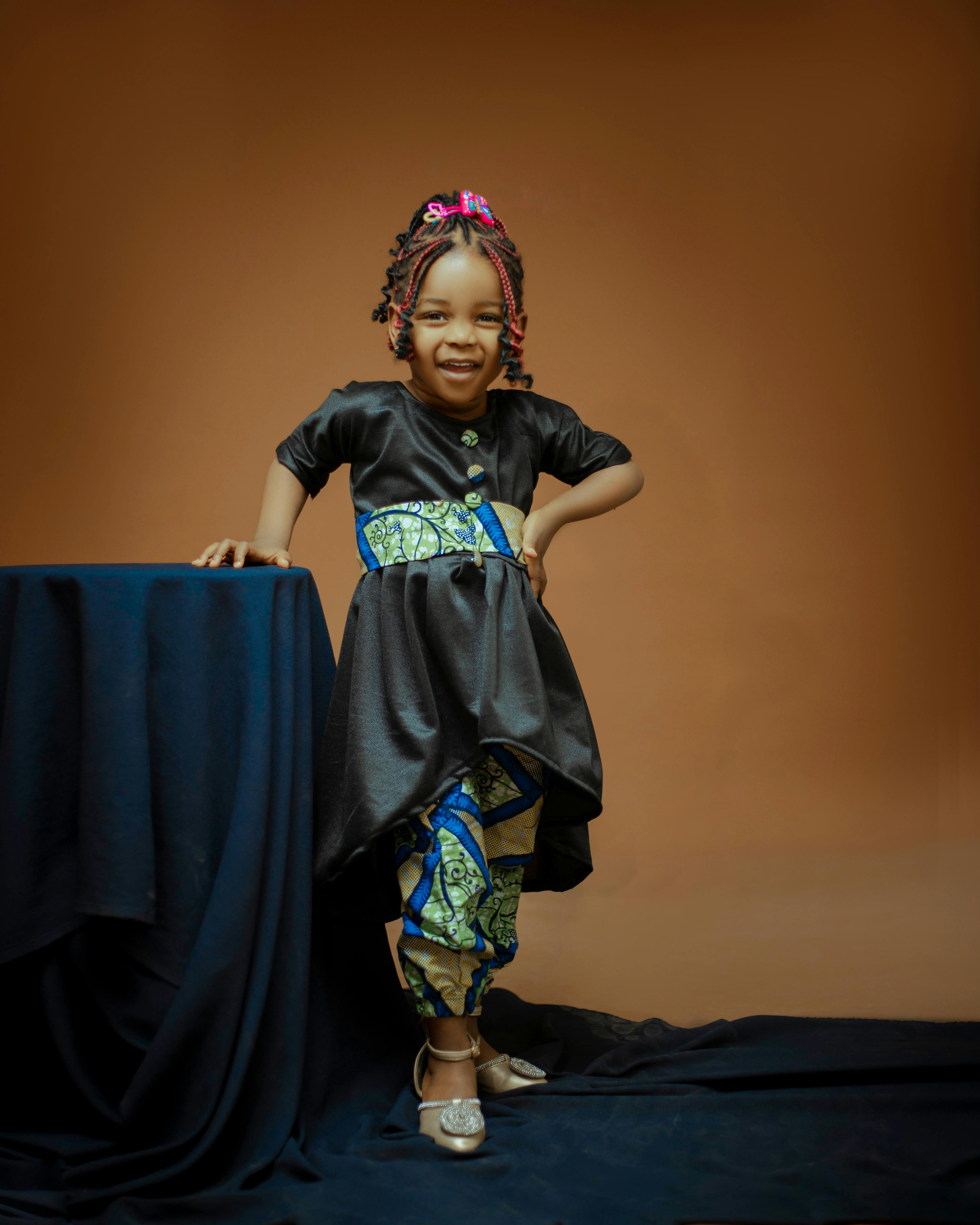Little Model Posing in a Black Dress and Patterned Pants · Free Stock Photo