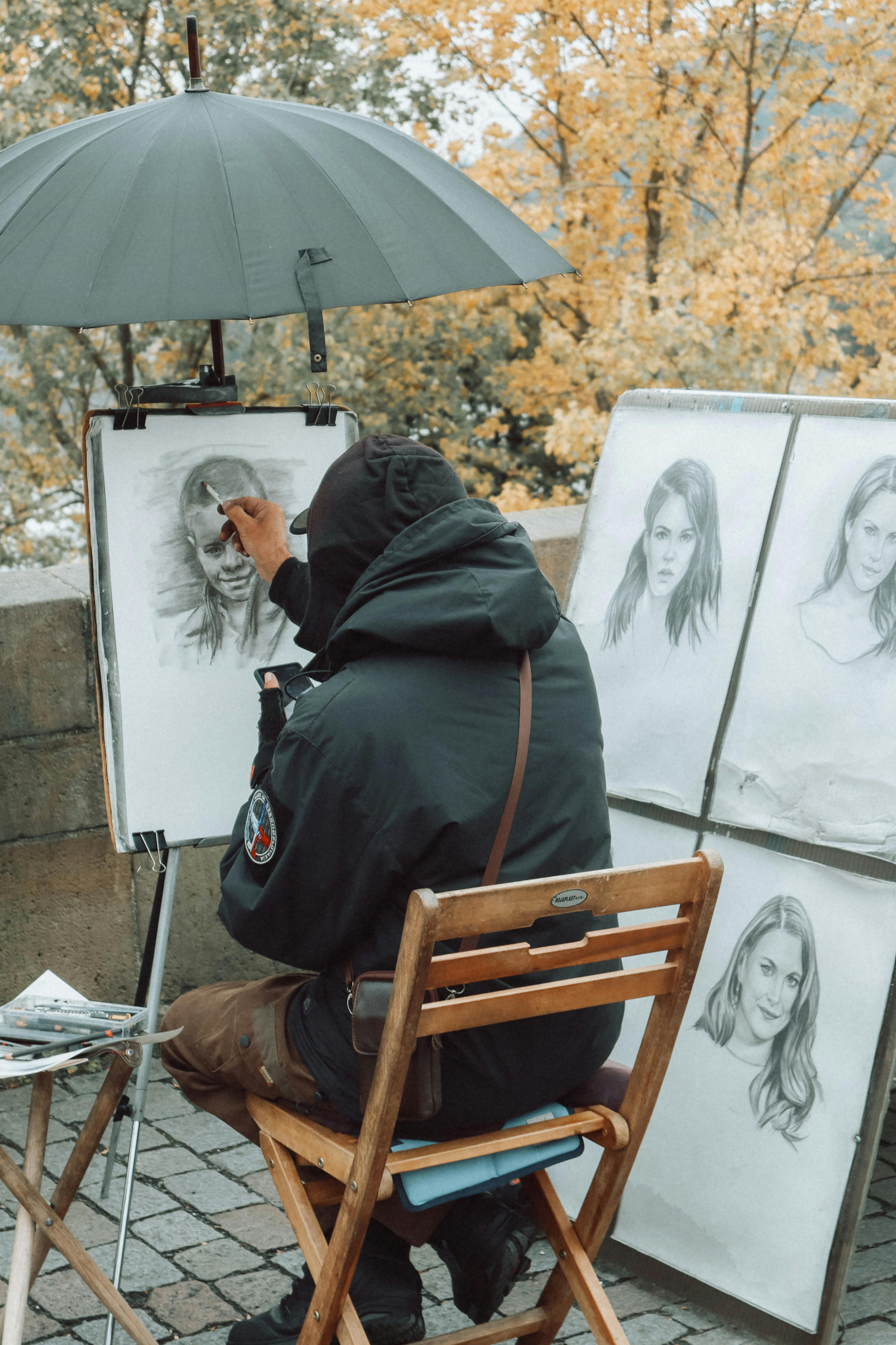 Back View of a Man Drawing Portraits on a Street · Free Stock Photo