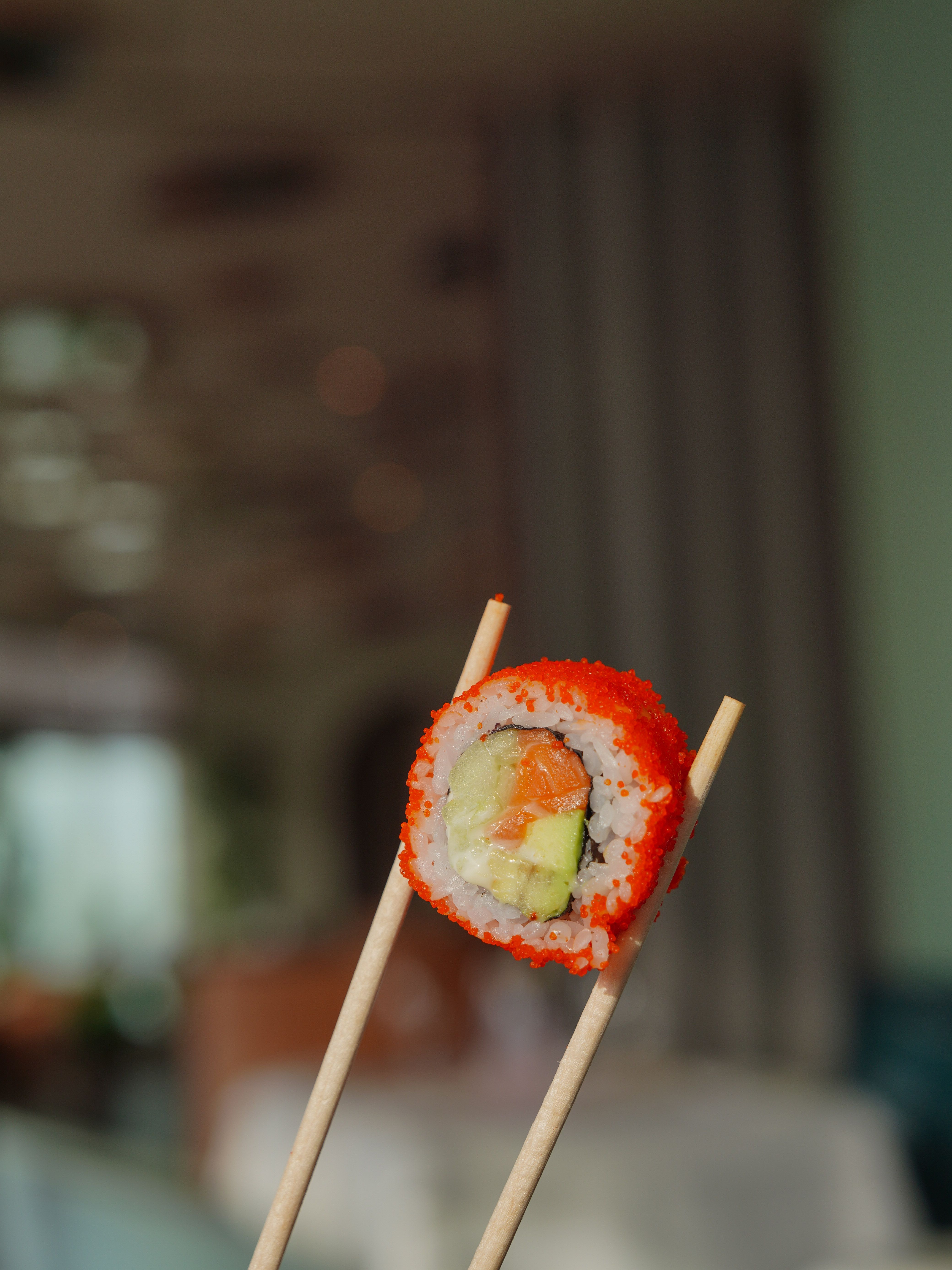 A sushi roll is held up with chopsticks · Free Stock Photo
