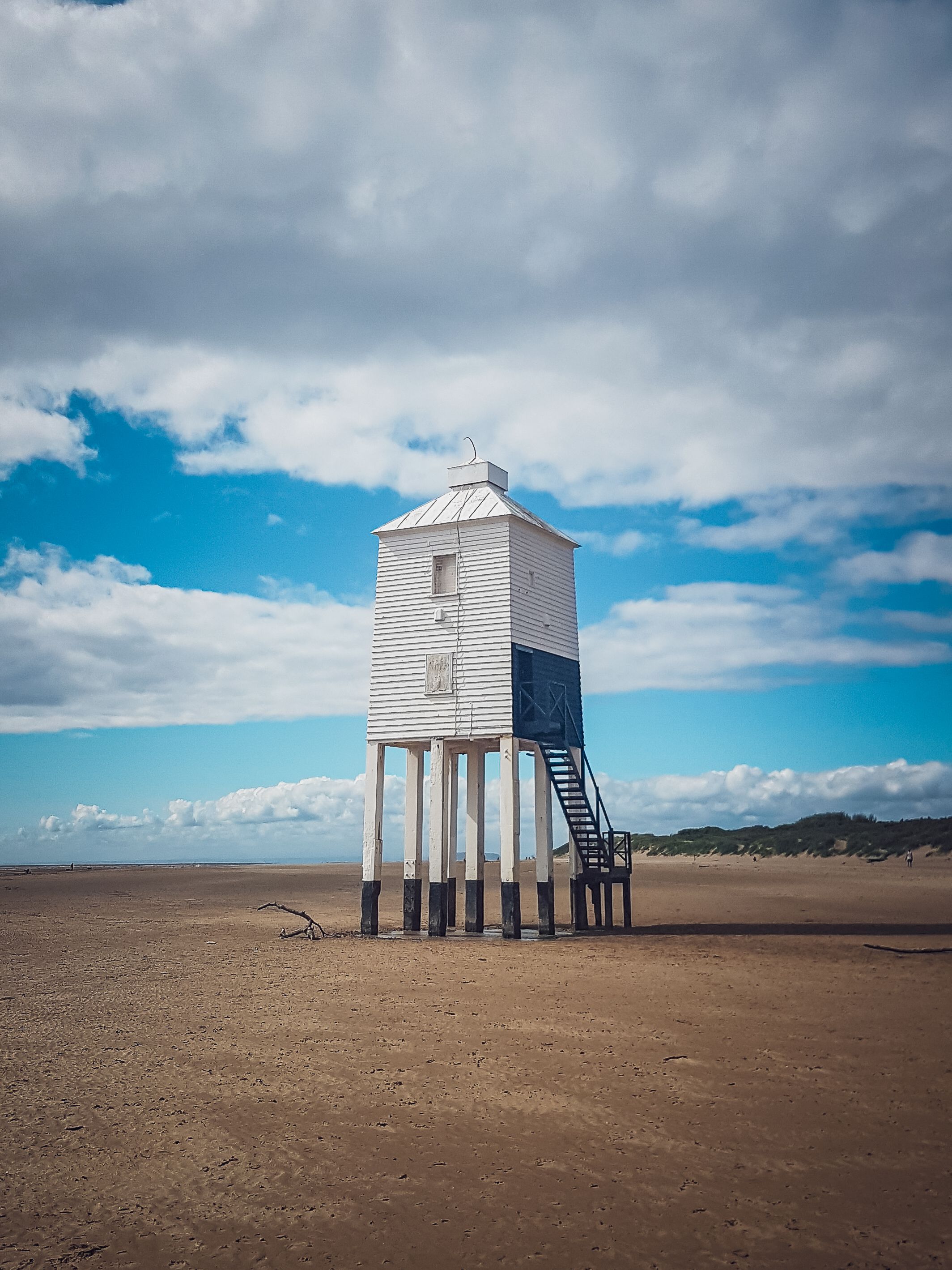 A white lighthouse on a beach with blue sky · Free Stock Photo