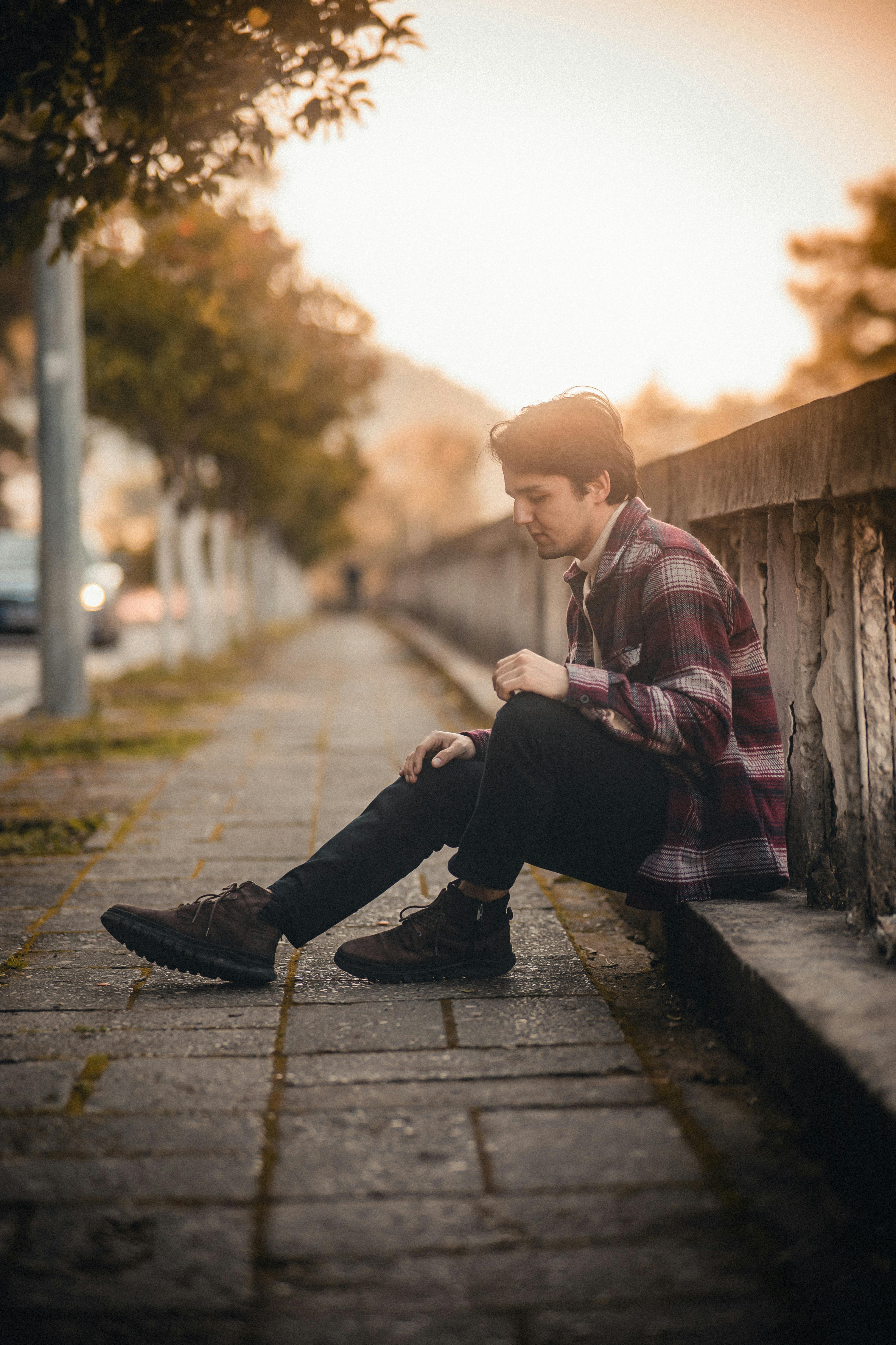 Man Sitting on Sidewalk at Sunset · Free Stock Photo