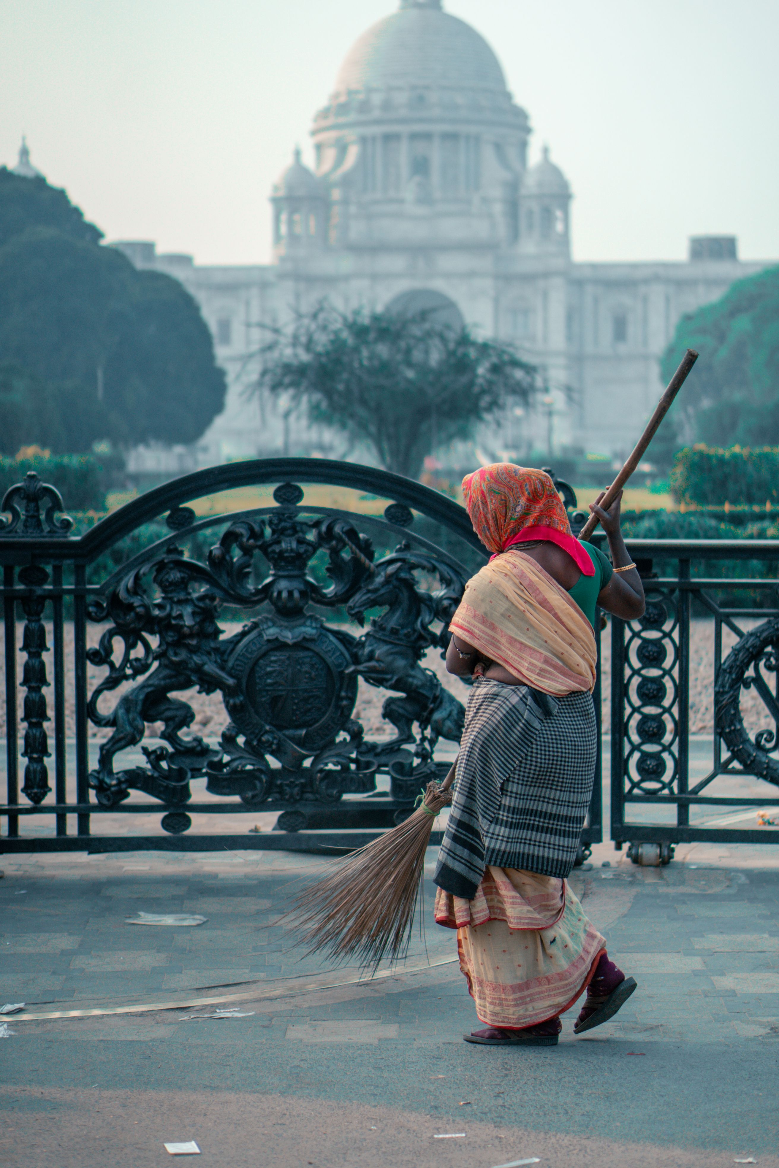 Building with Dome behind Cleaner Walking with Broom · Free Stock Photo