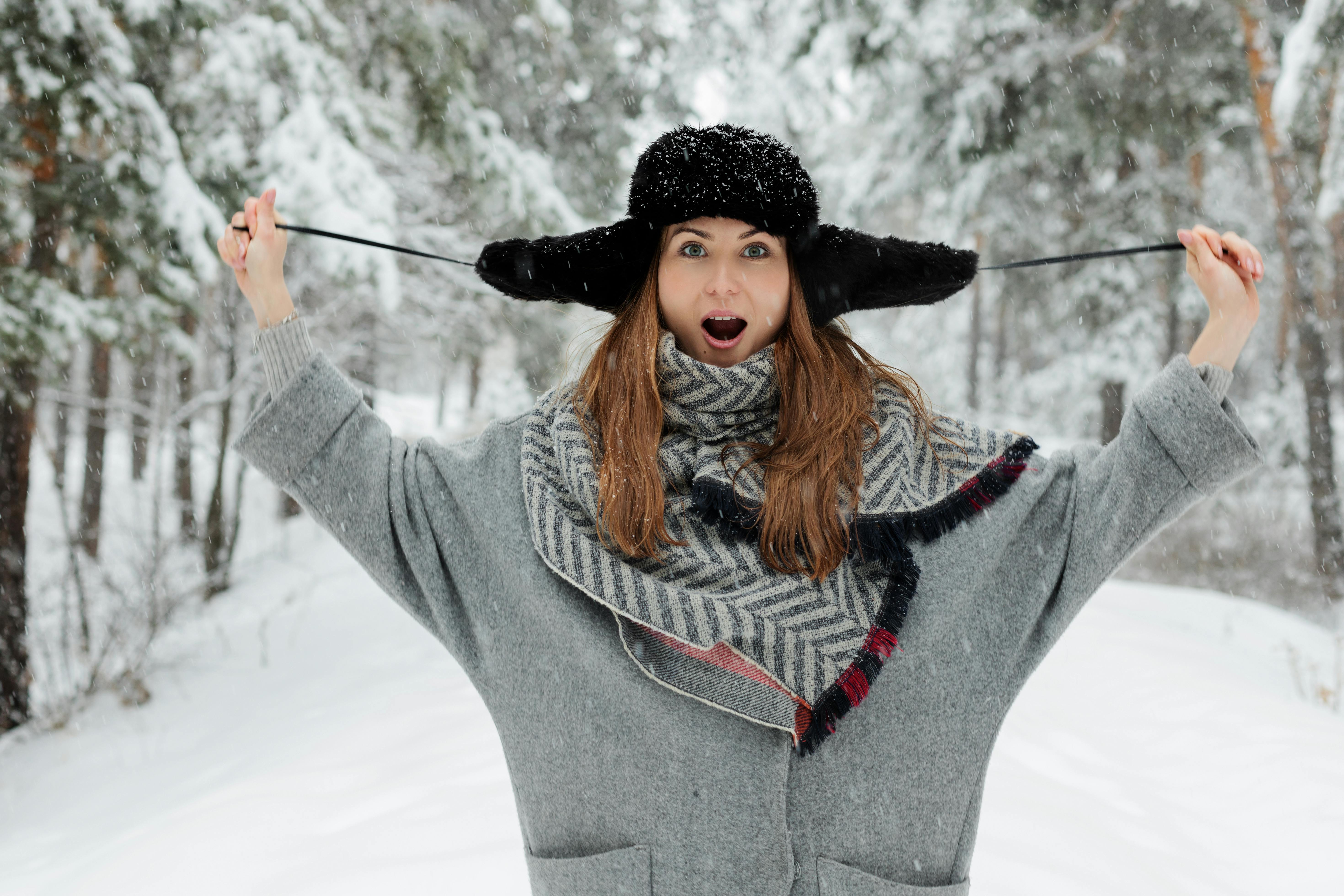A Beautiful Woman Pulling the Strings of Her Trapper Hat · Free Stock Photo