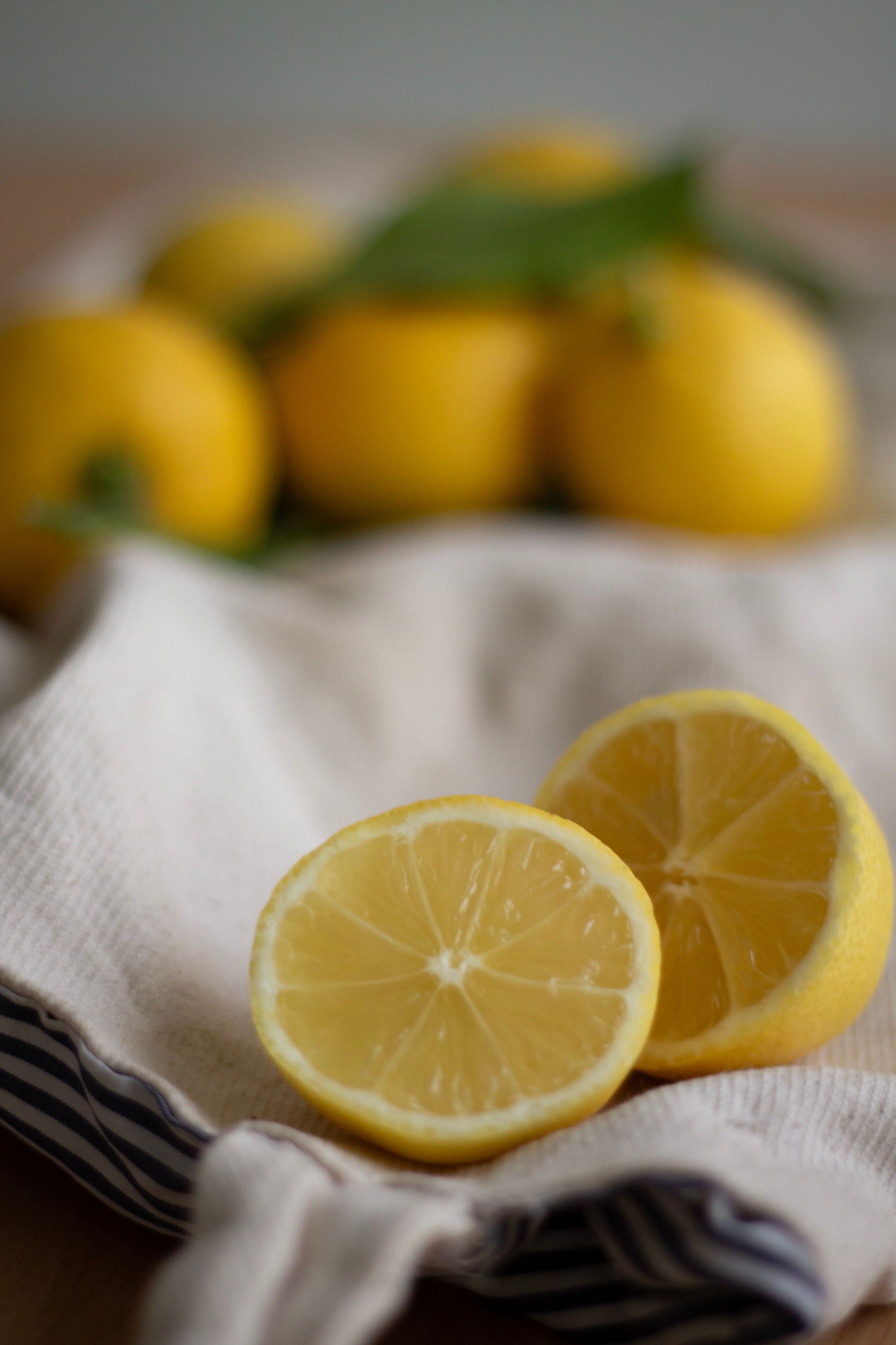 Lemons and lemon slices near leaves · Free Stock Photo