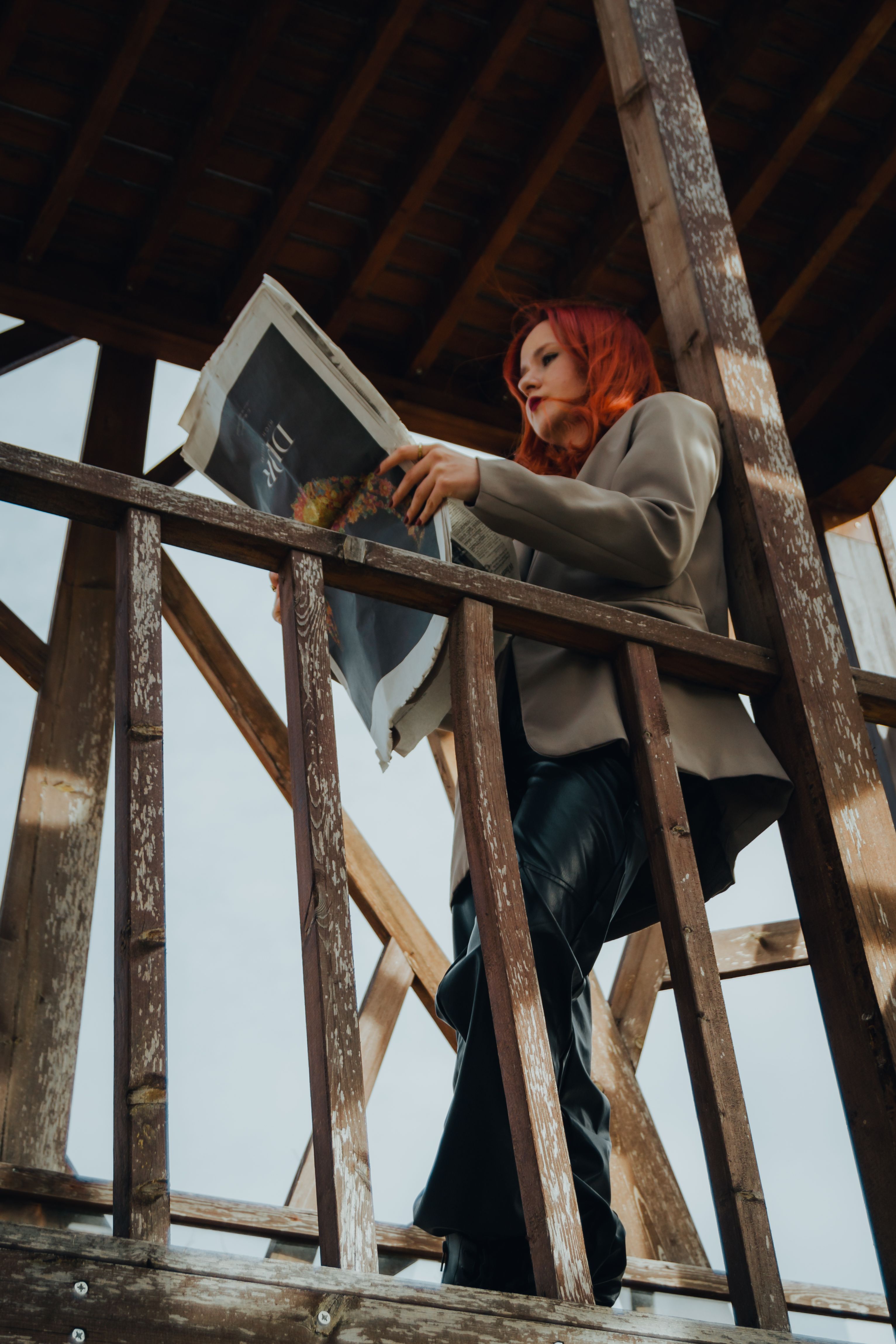Redhead Woman Standing behind Railing and Reading Newspaper · Free ...