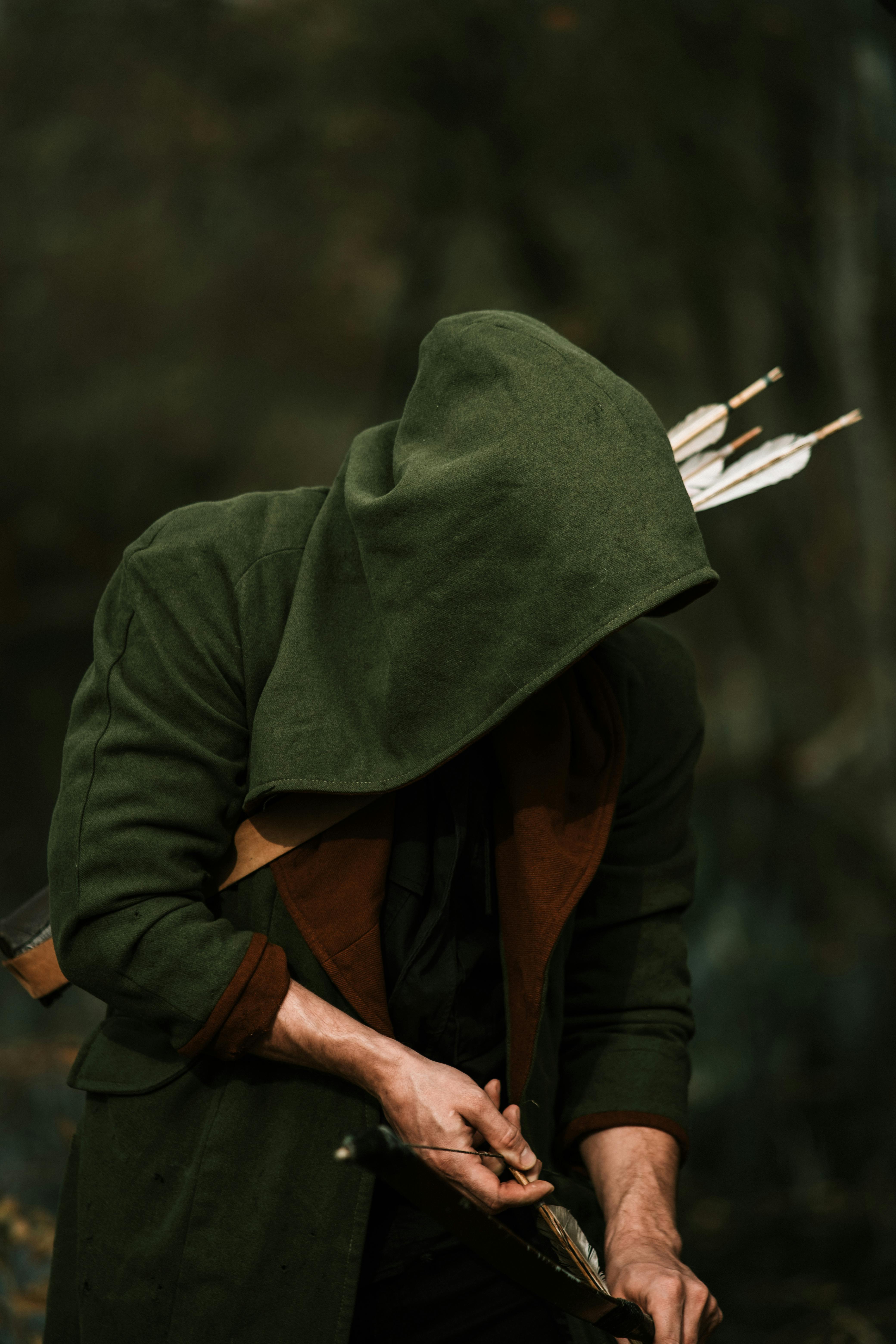 Man Wearing a Hood, Holding a Bow and Arrows in a Forest · Free Stock Photo