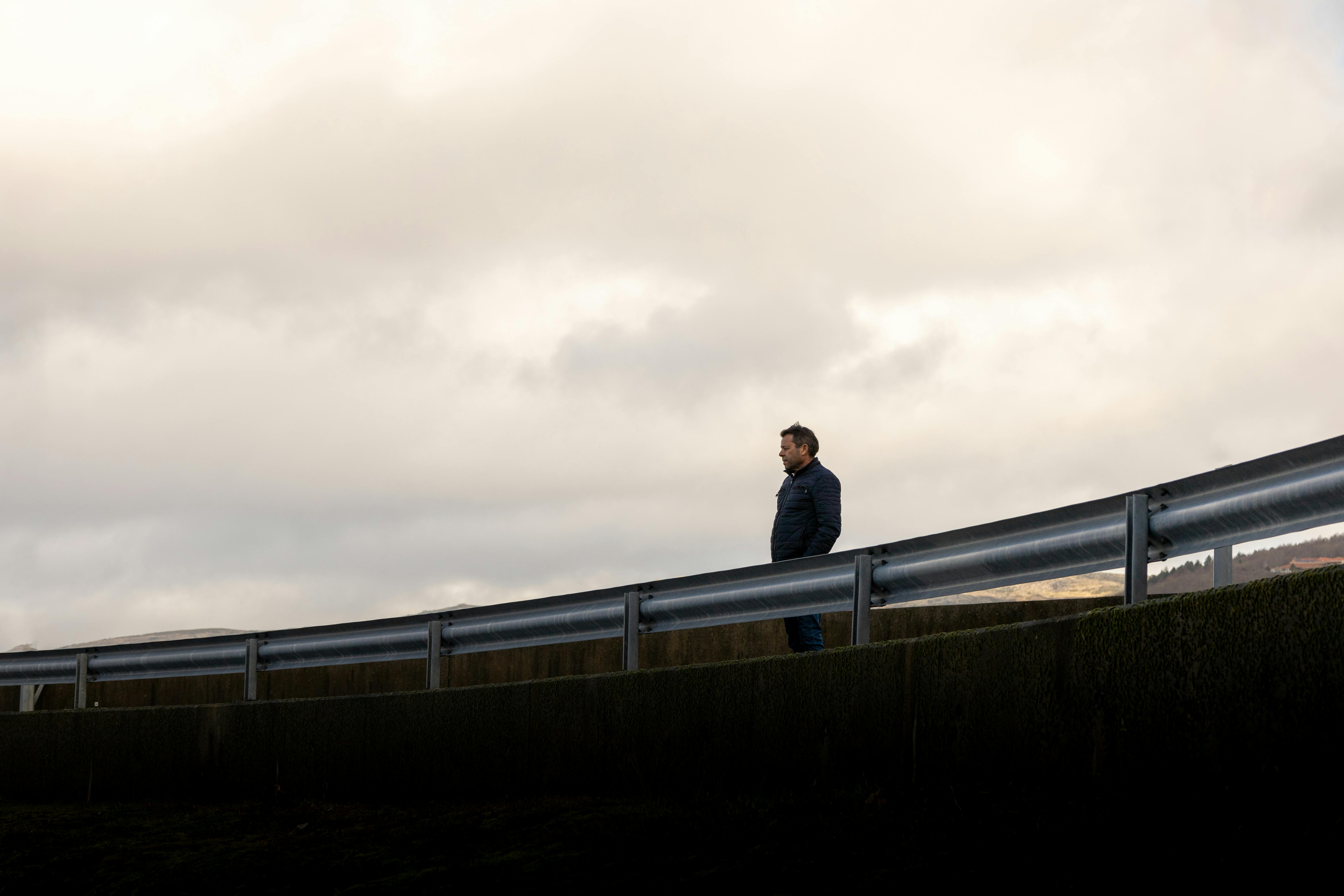 Man Standing by the Road Barrier · Free Stock Photo