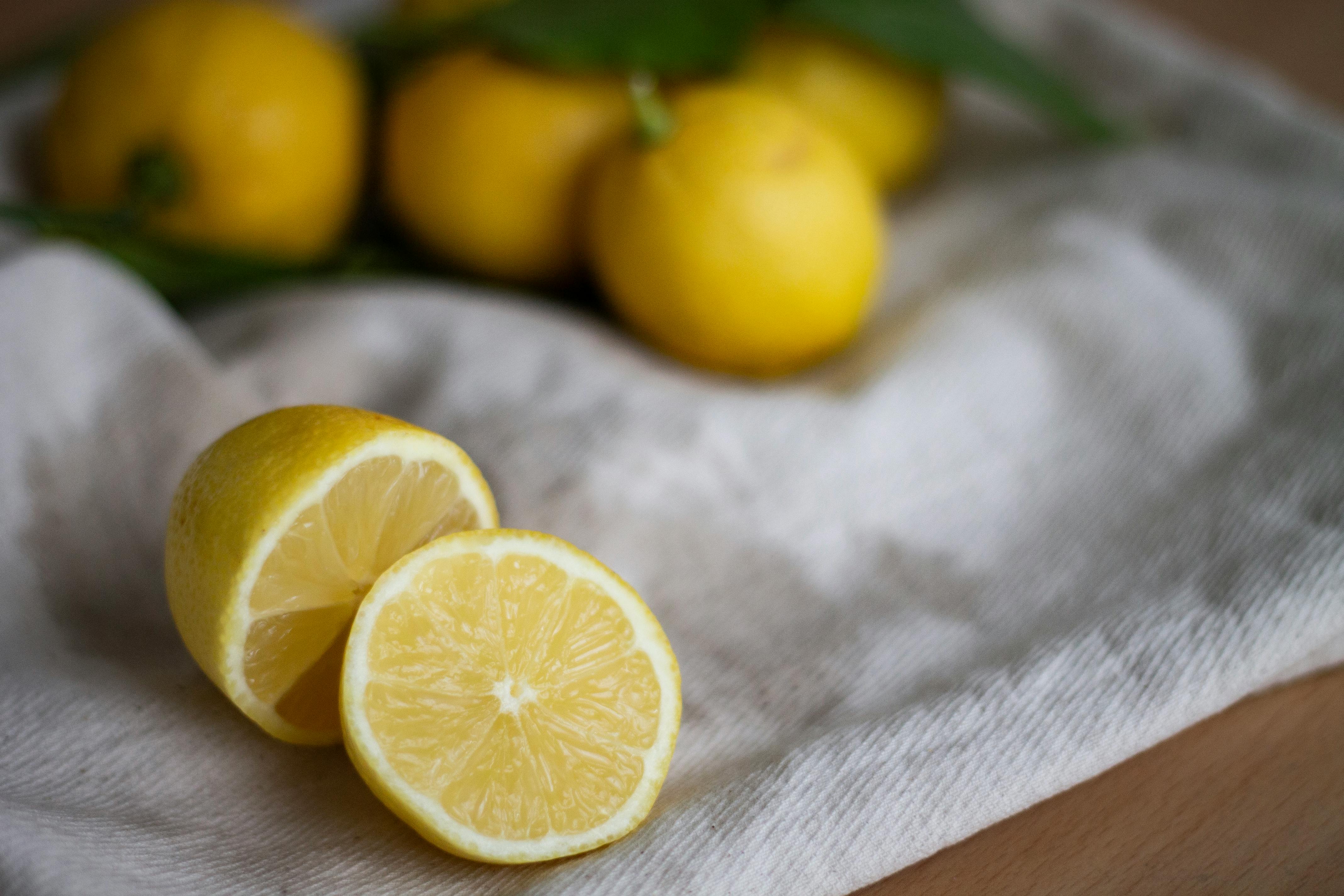 Three Lemons Beside Sliced Lemon on Tree Slab · Free Stock Photo
