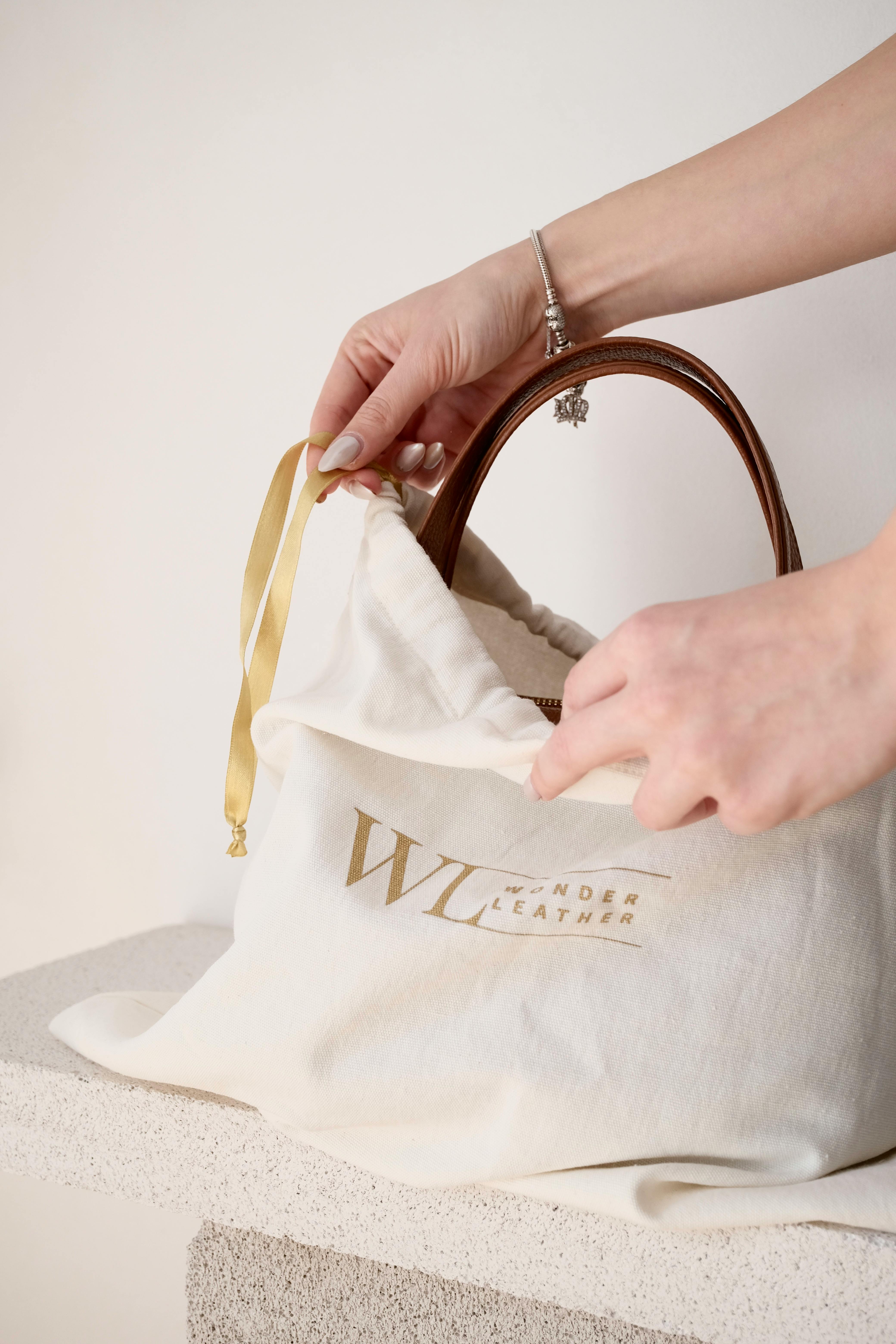 Hands Holding a Cover of a Brown Handbag · Free Stock Photo
