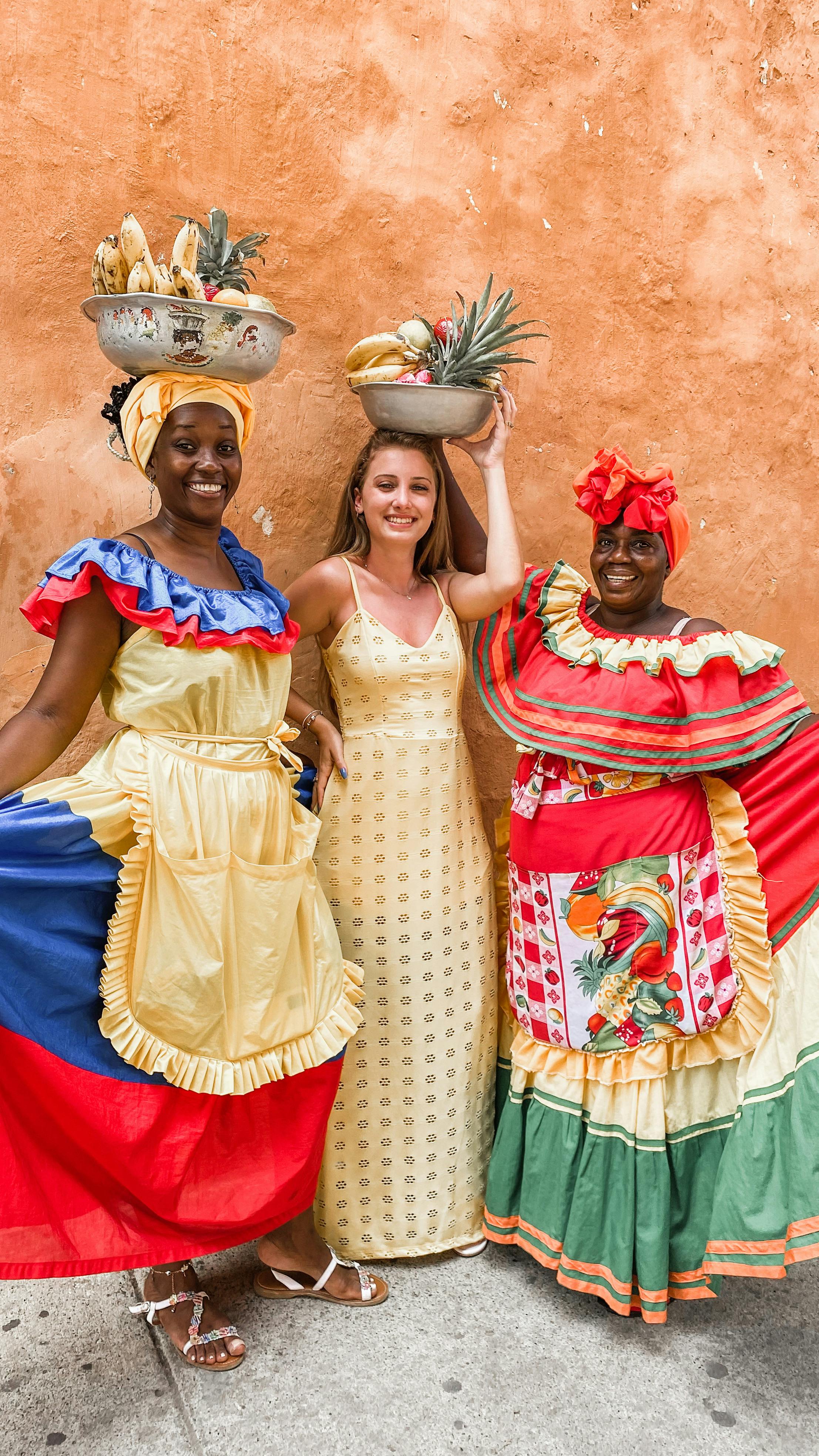 Three women in colorful costumes pose for a photo · Free Stock Photo