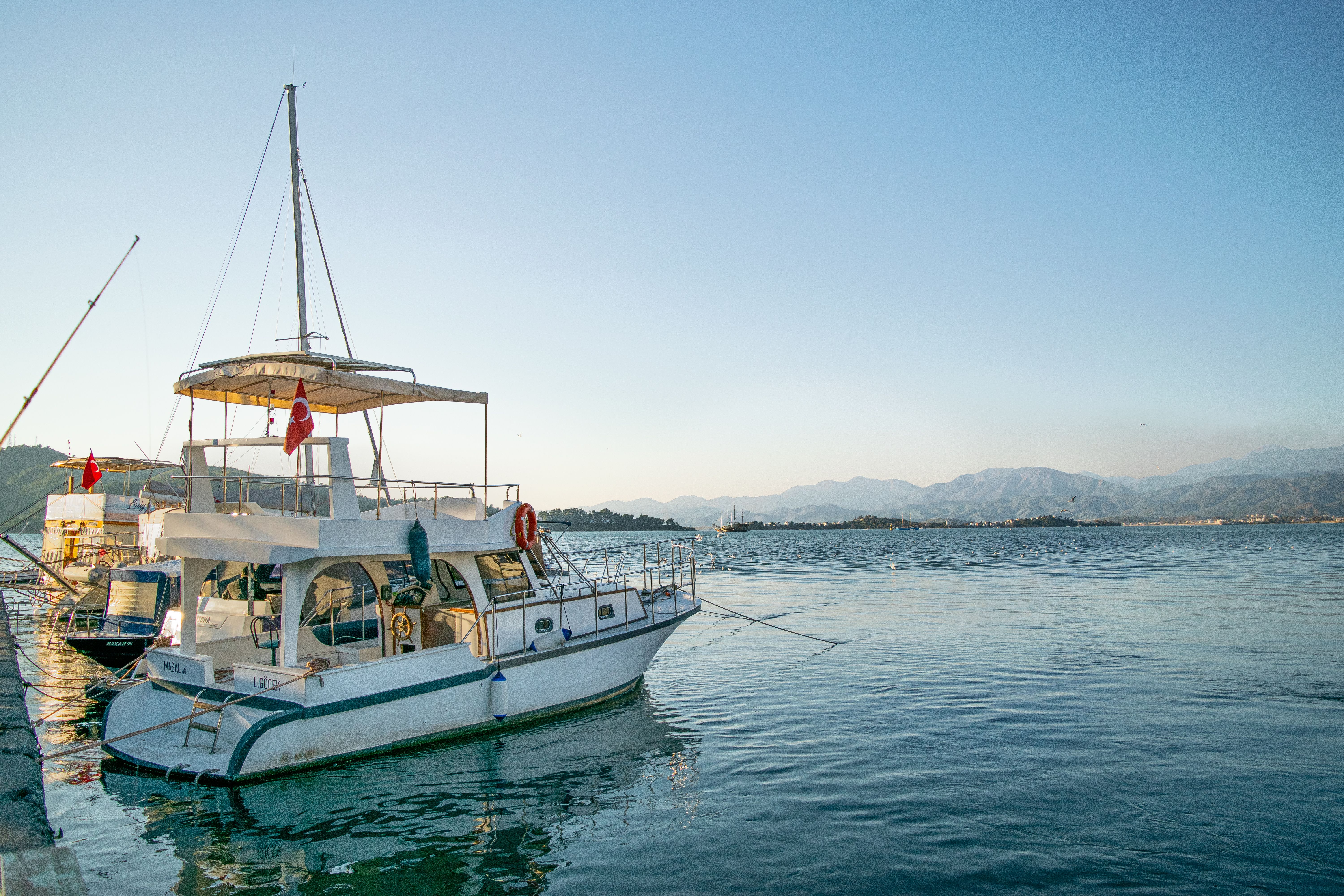 A boat docked at a dock with mountains in the background · Free Stock Photo
