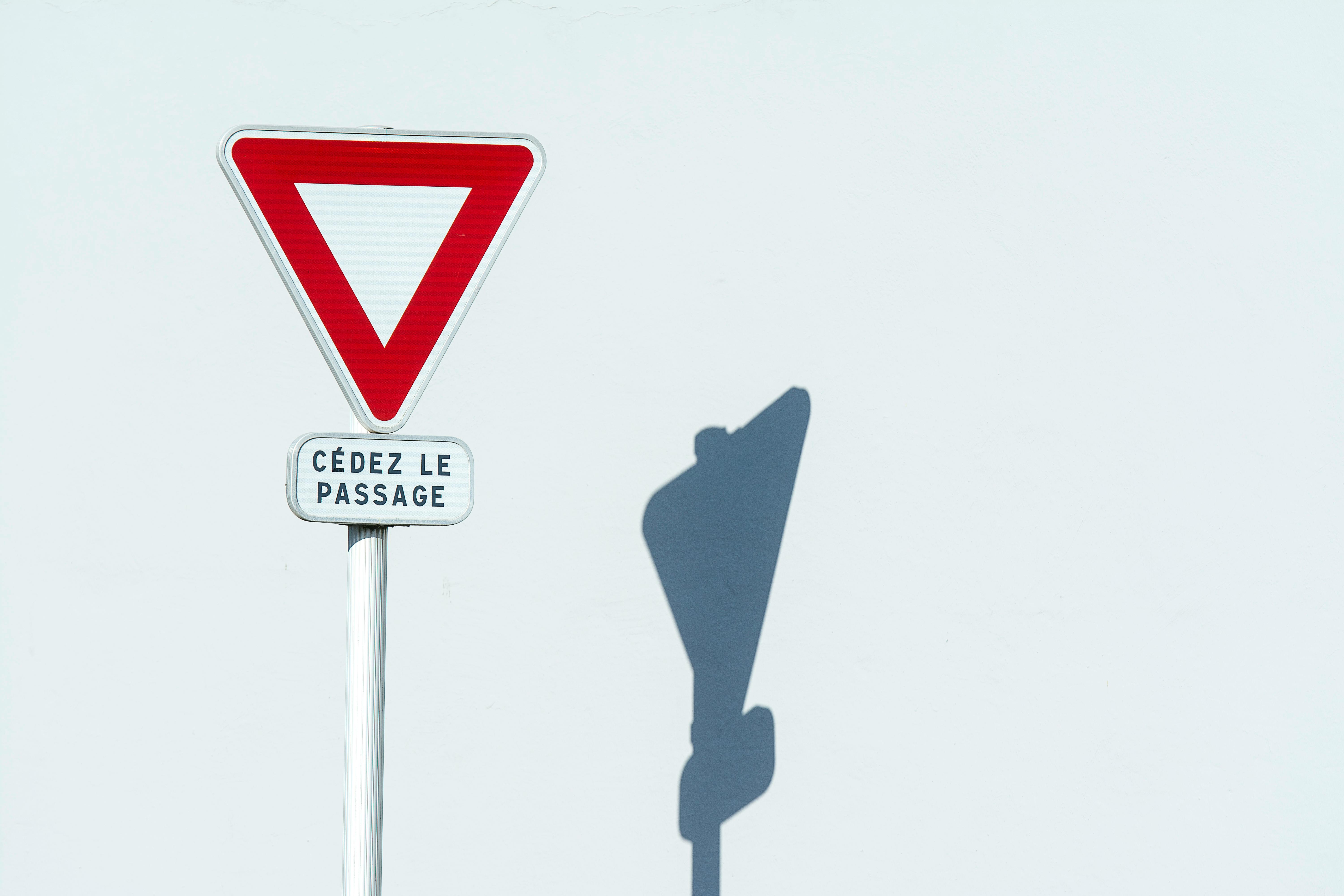 Road Sign and Shadow on White Wall · Free Stock Photo