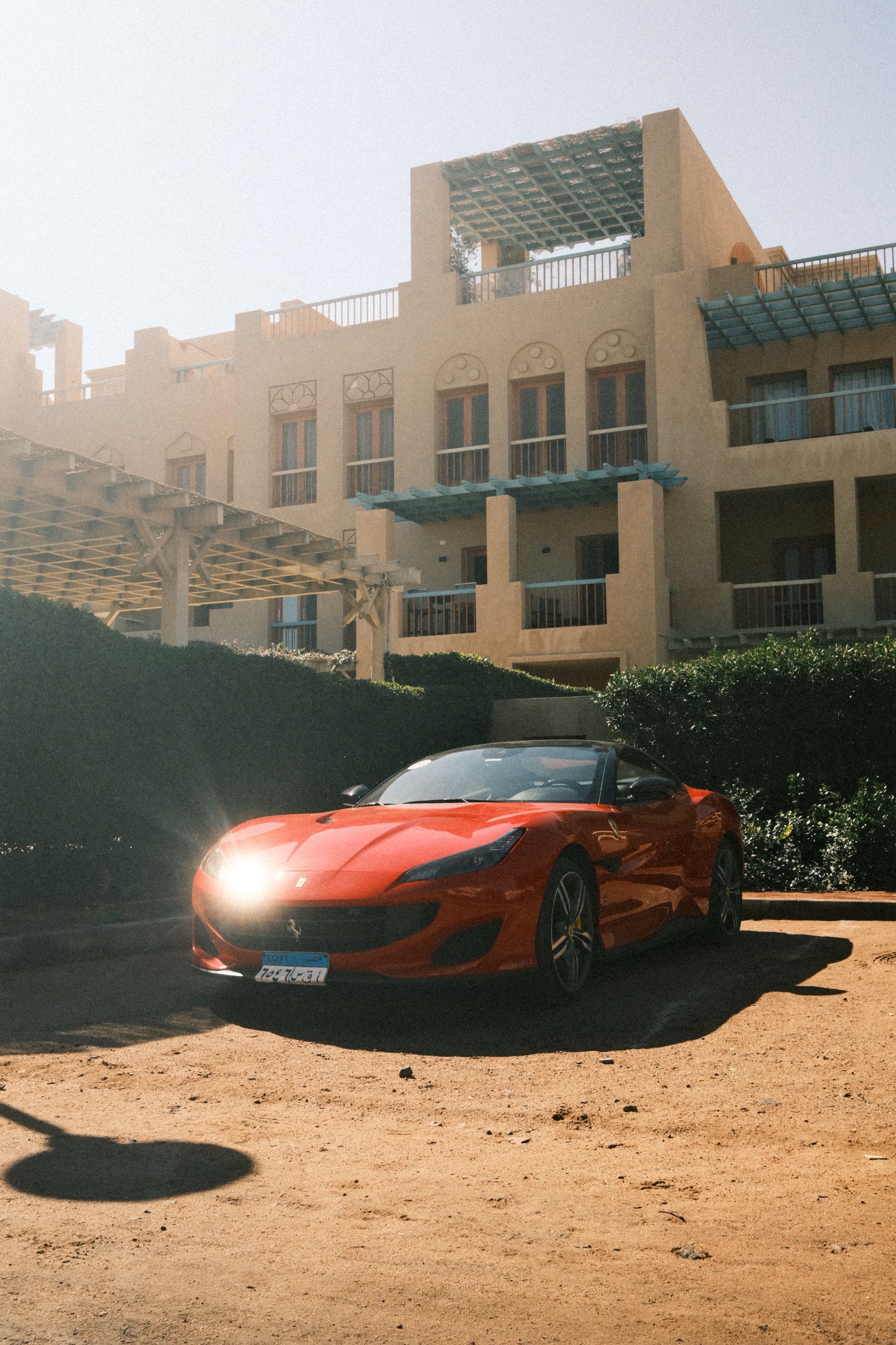Red, Sunlit Ferrari Parked near Building · Free Stock Photo