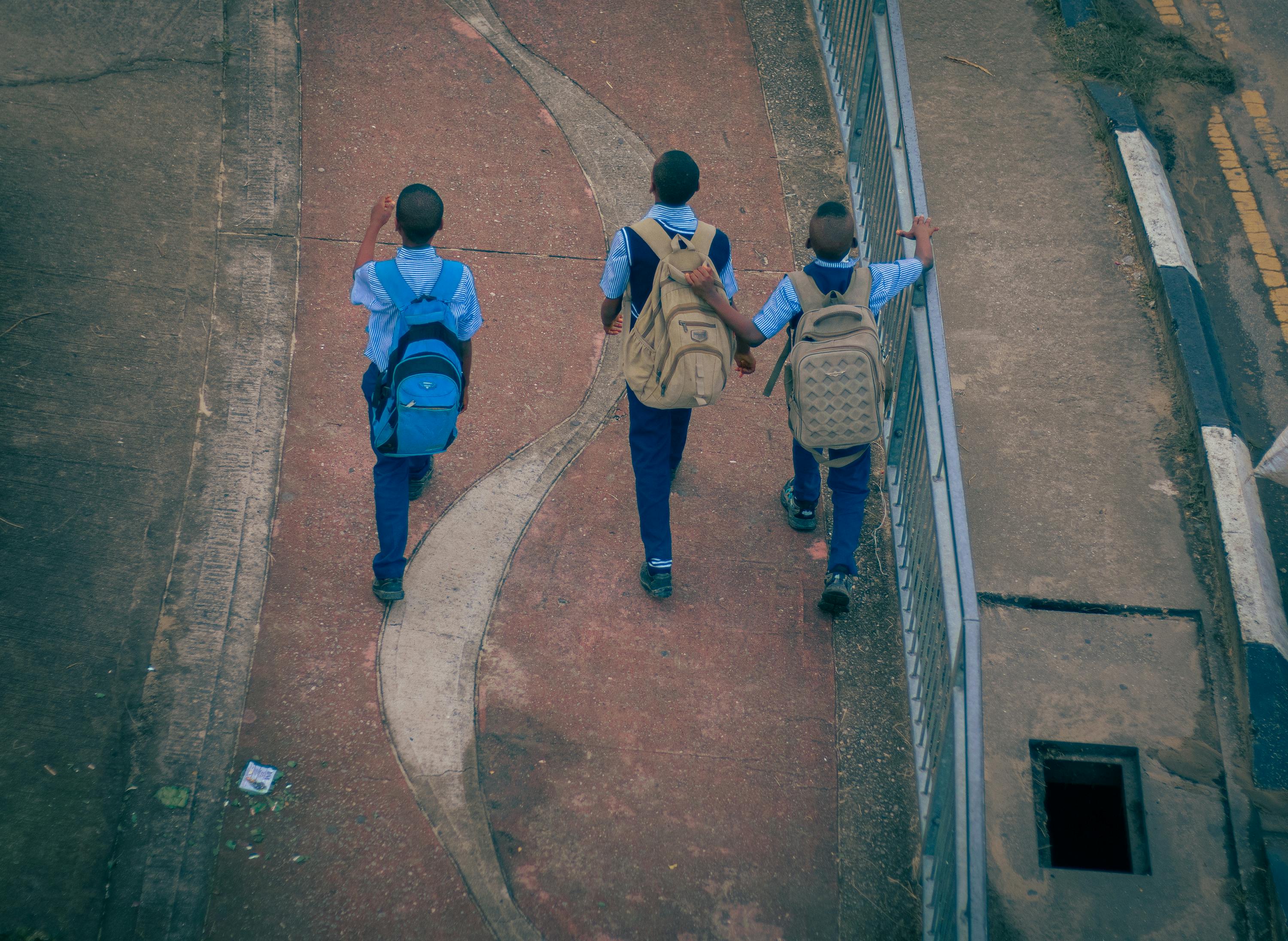 Boys with Backpacks Walking on Pavement · Free Stock Photo