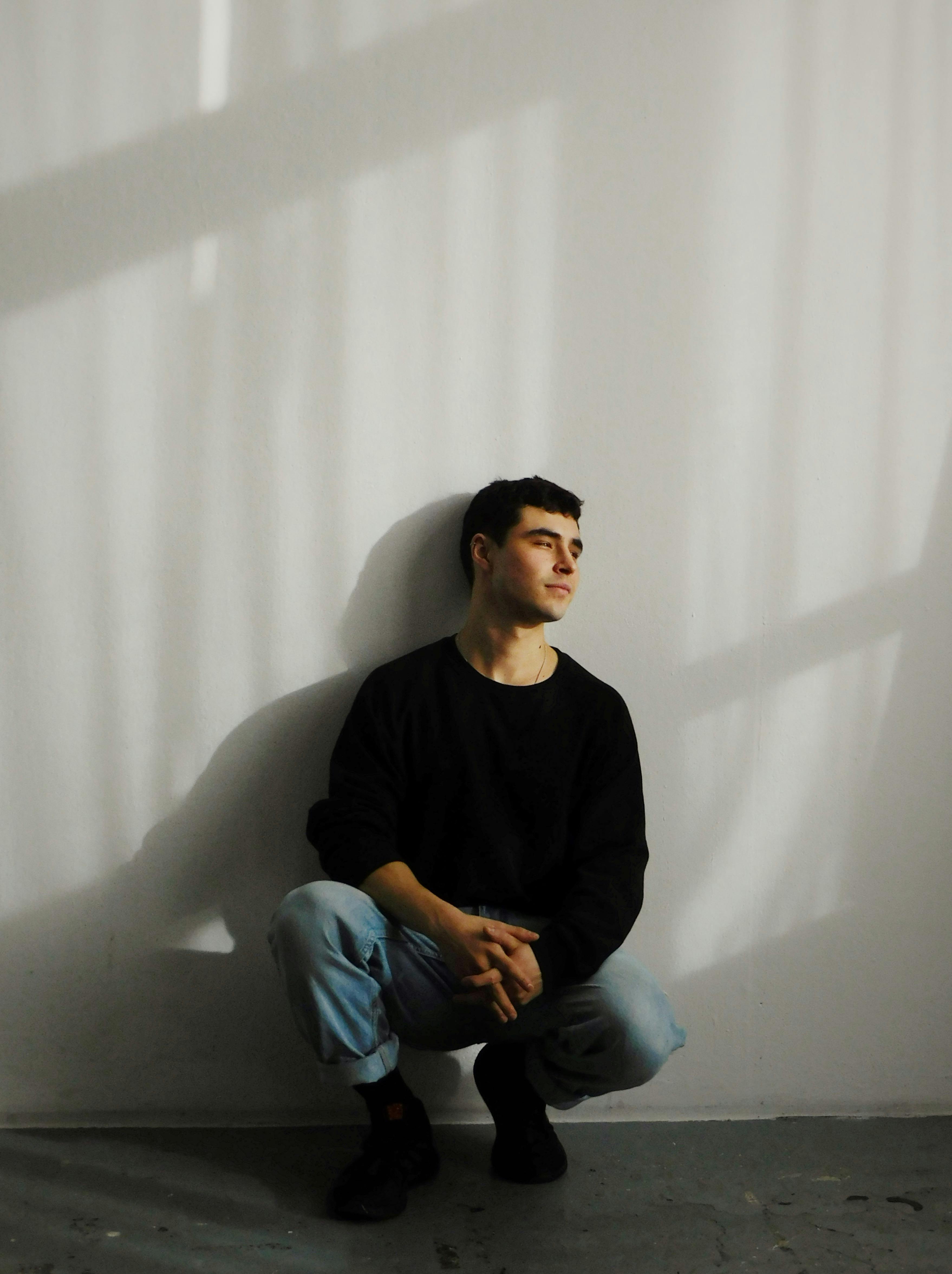 Crouching Man Leaning on Wall · Free Stock Photo