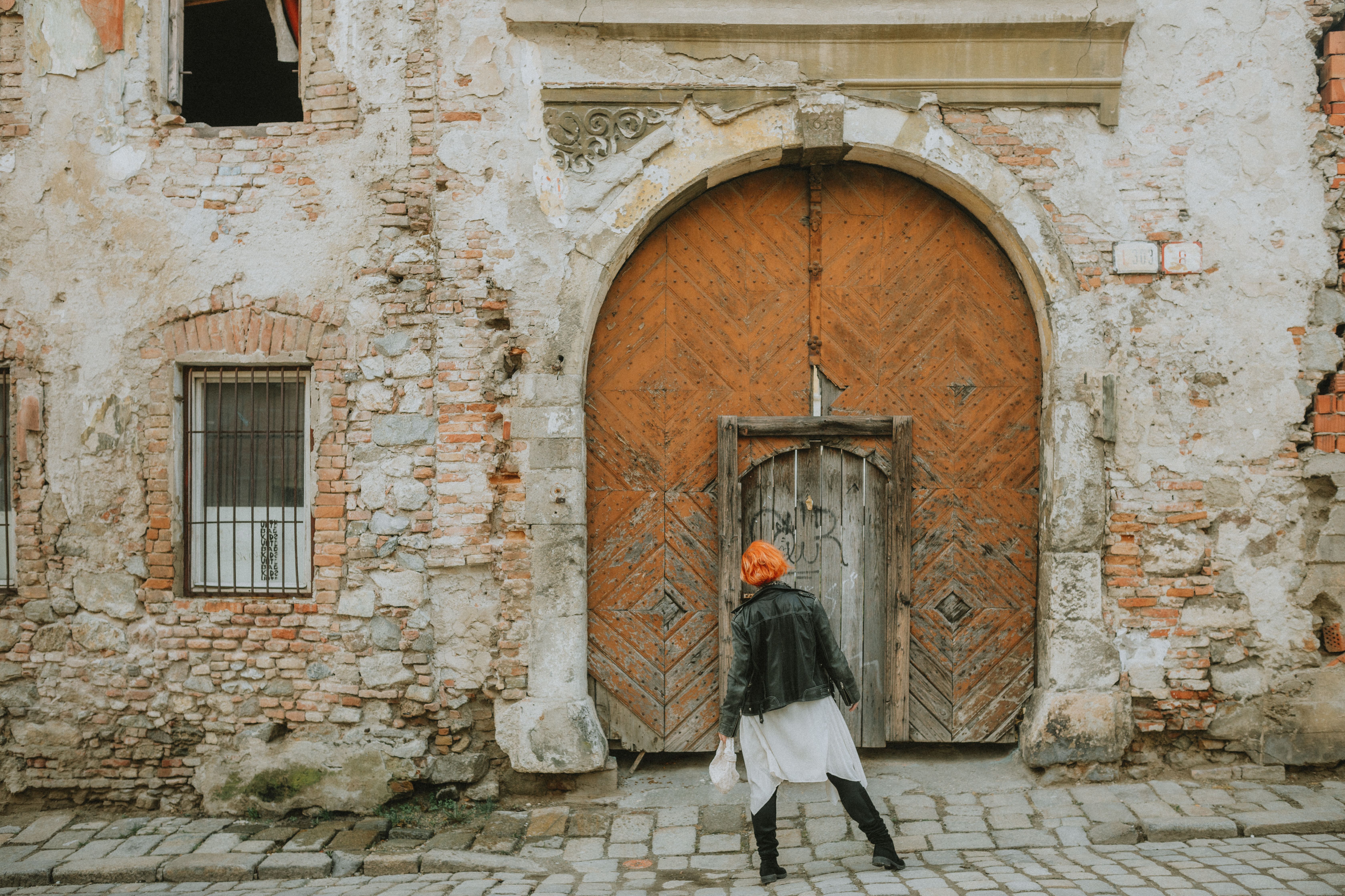 Woman Looking at Decrepit Wooden Door in Bratislava · Free Stock Photo