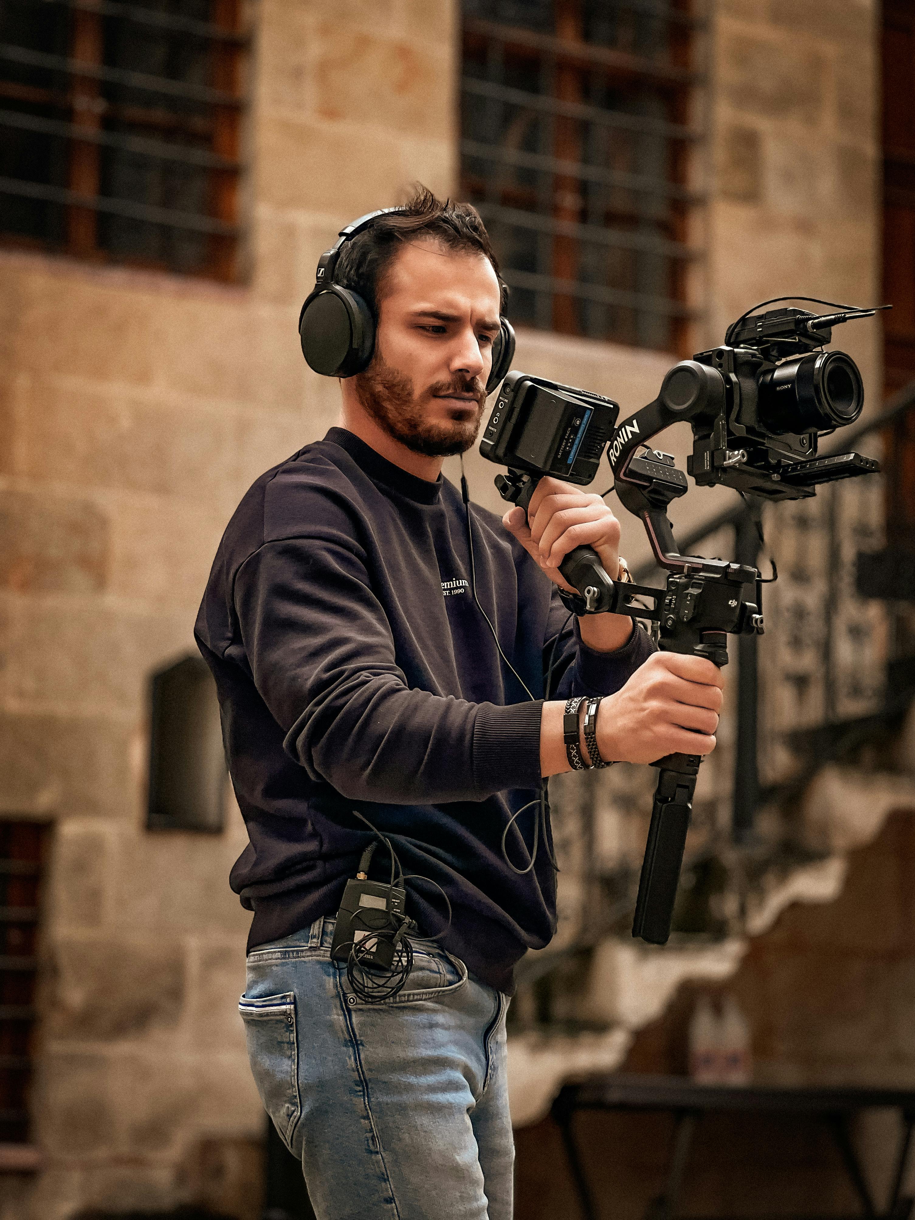 Man Standing in Headphones and with Camera on Gimbal · Free Stock Photo