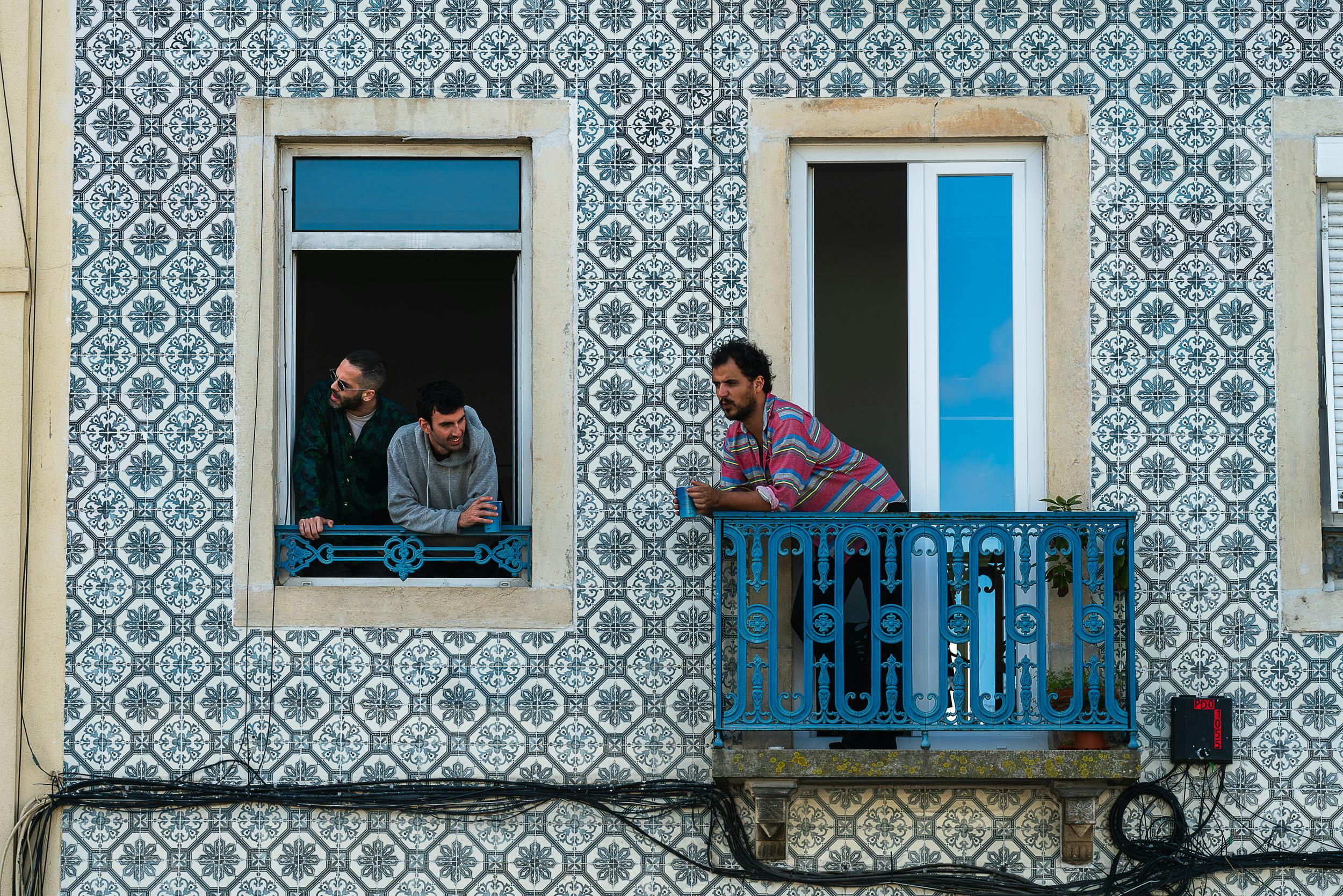 Men in Window Next to Man Standing on Balcony · Free Stock Photo