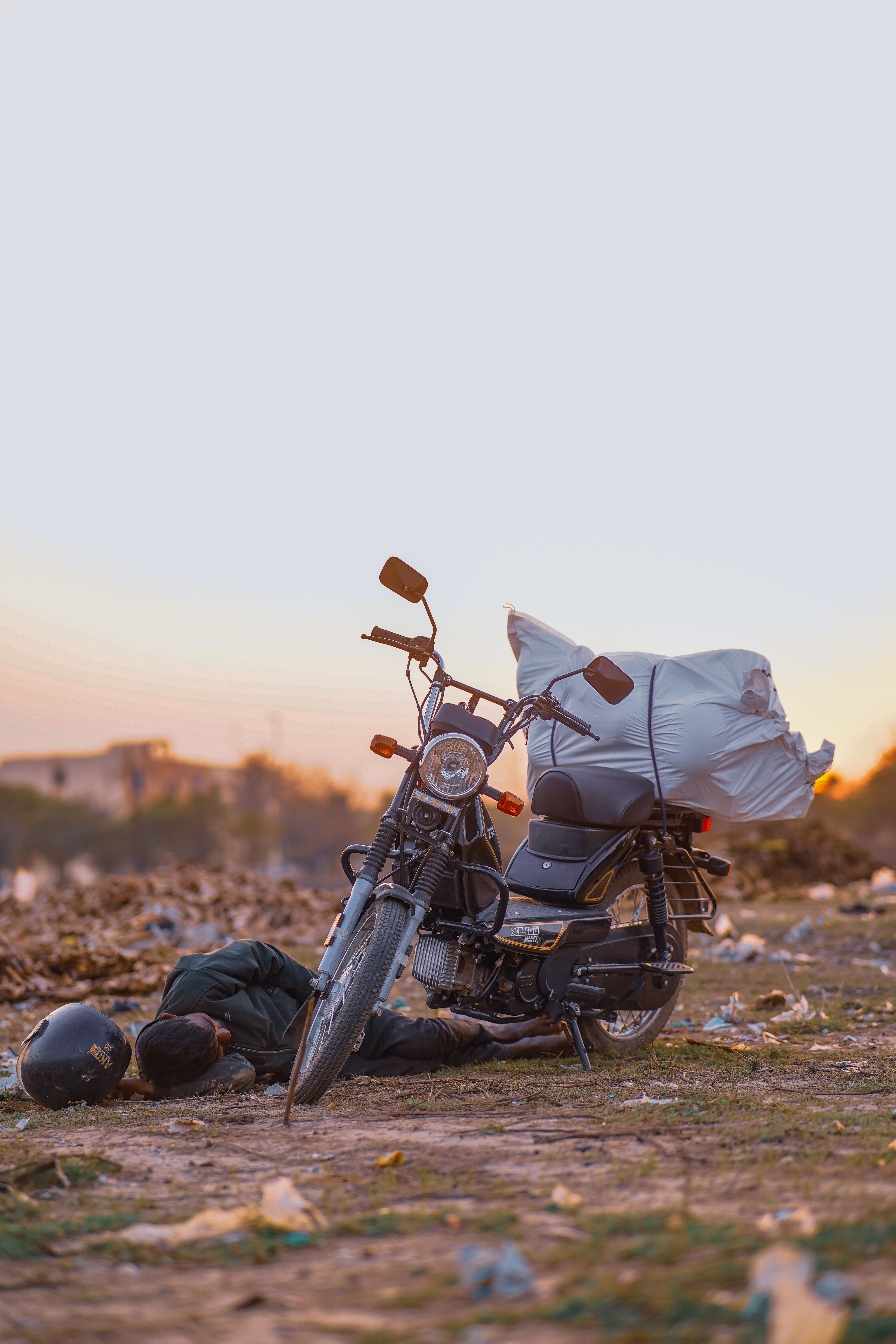 Man Lying Down under Motorbike on Field and Sleeping · Free Stock Photo