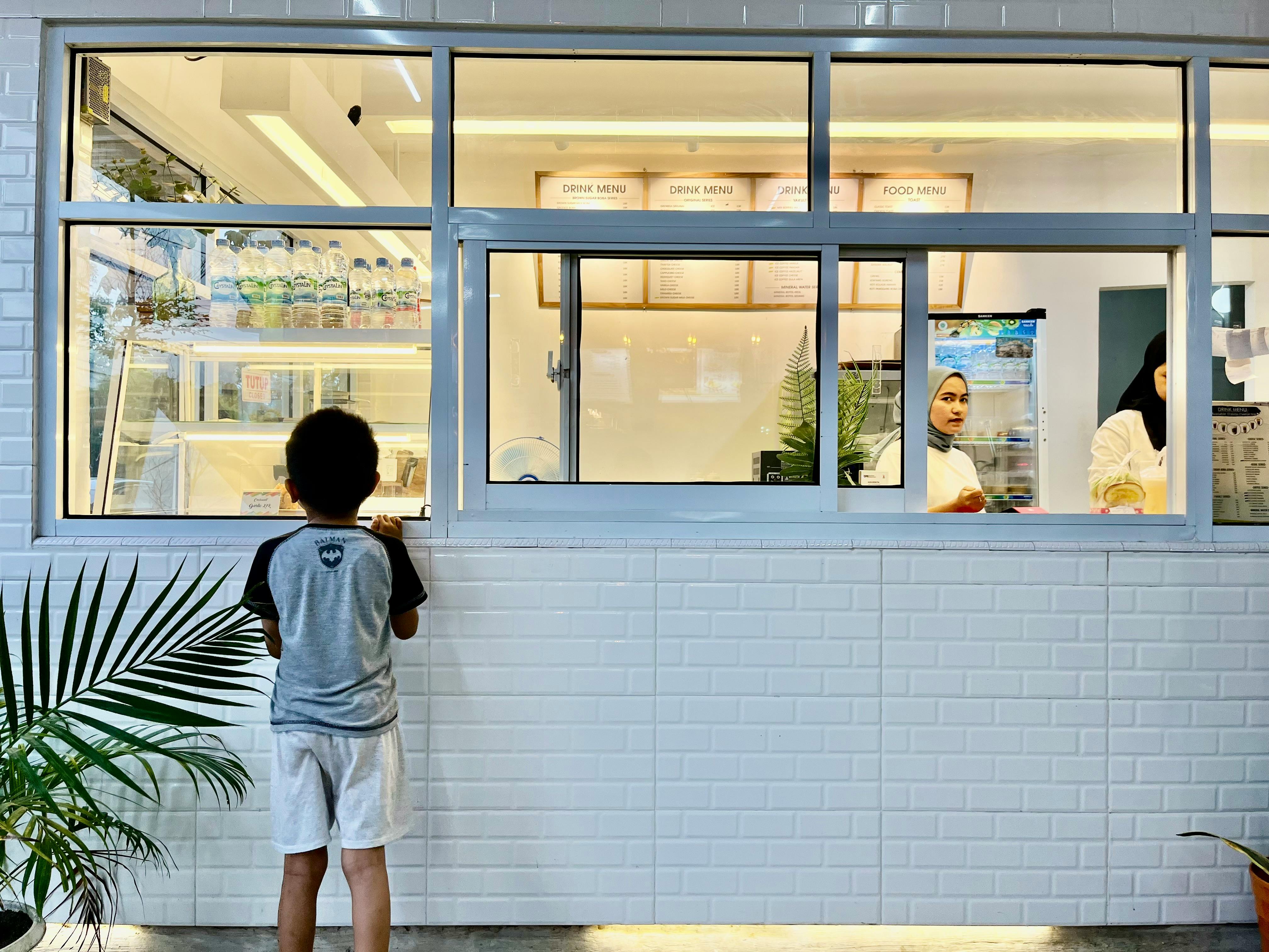 Boy Standing and Peeking through Cafe Windows · Free Stock Photo
