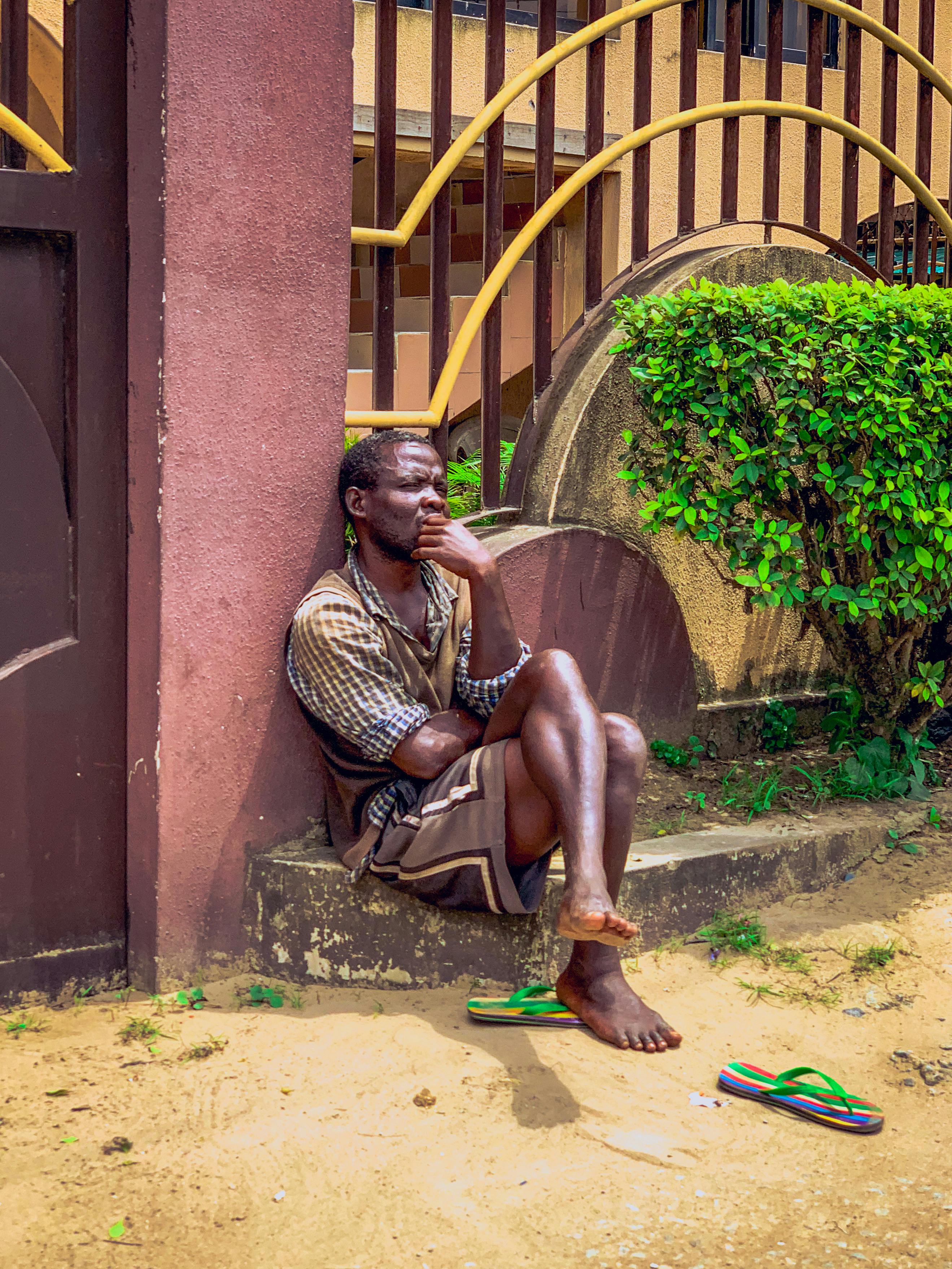 Pensive Man Sitting by Fence · Free Stock Photo