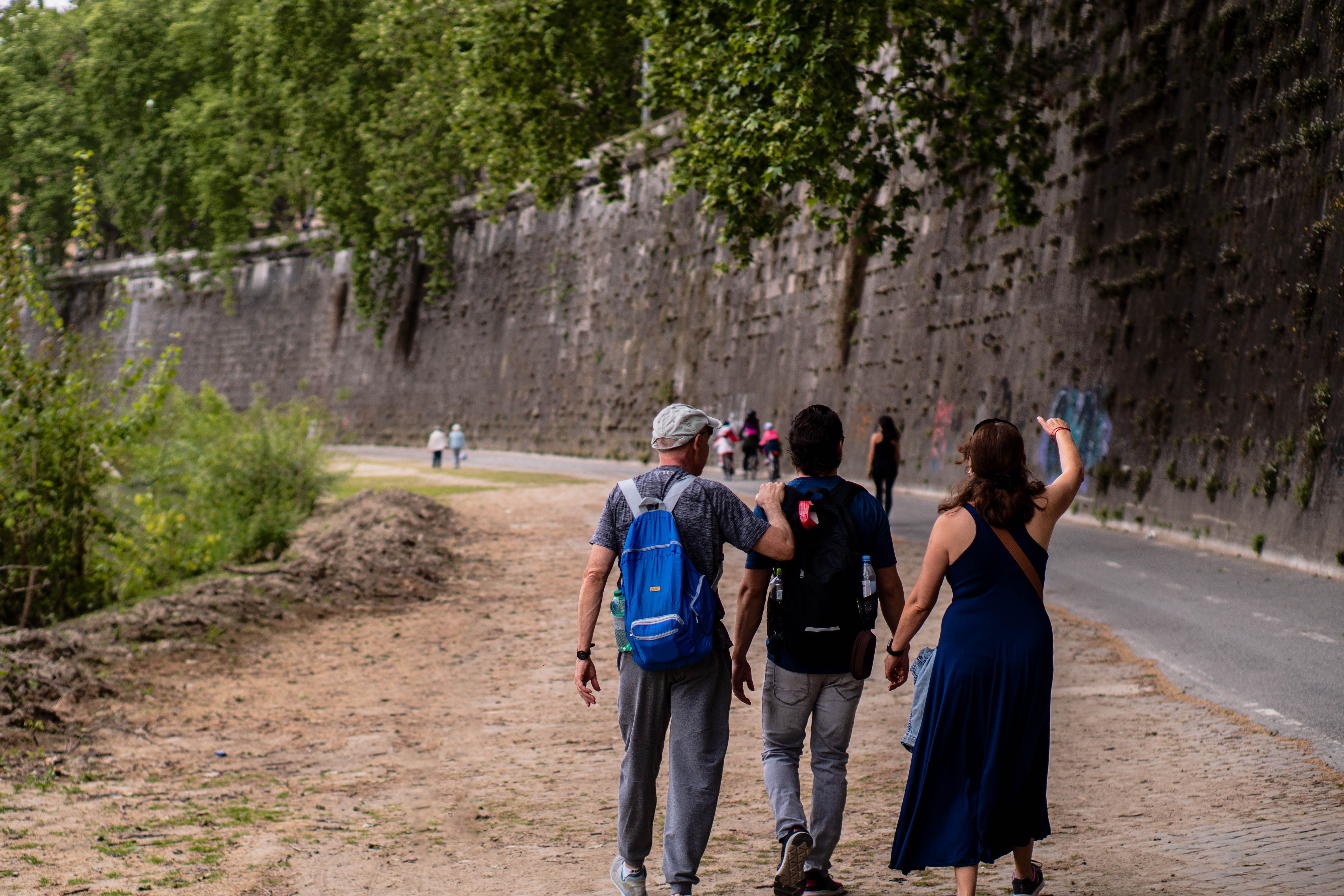 A group of people walking down a path near a wall · Free Stock Photo