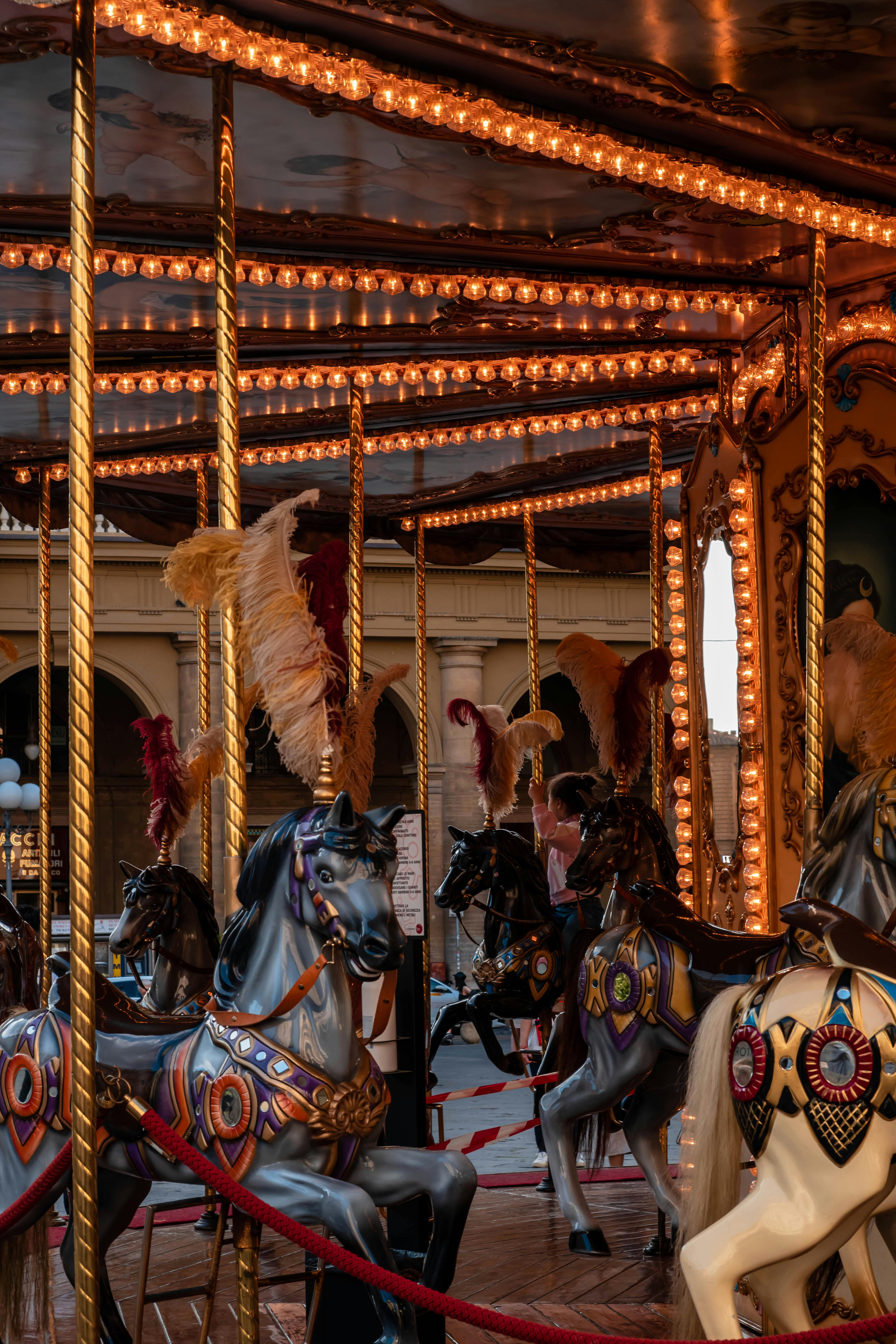 A carousel with horses and riders in the background · Free Stock Photo