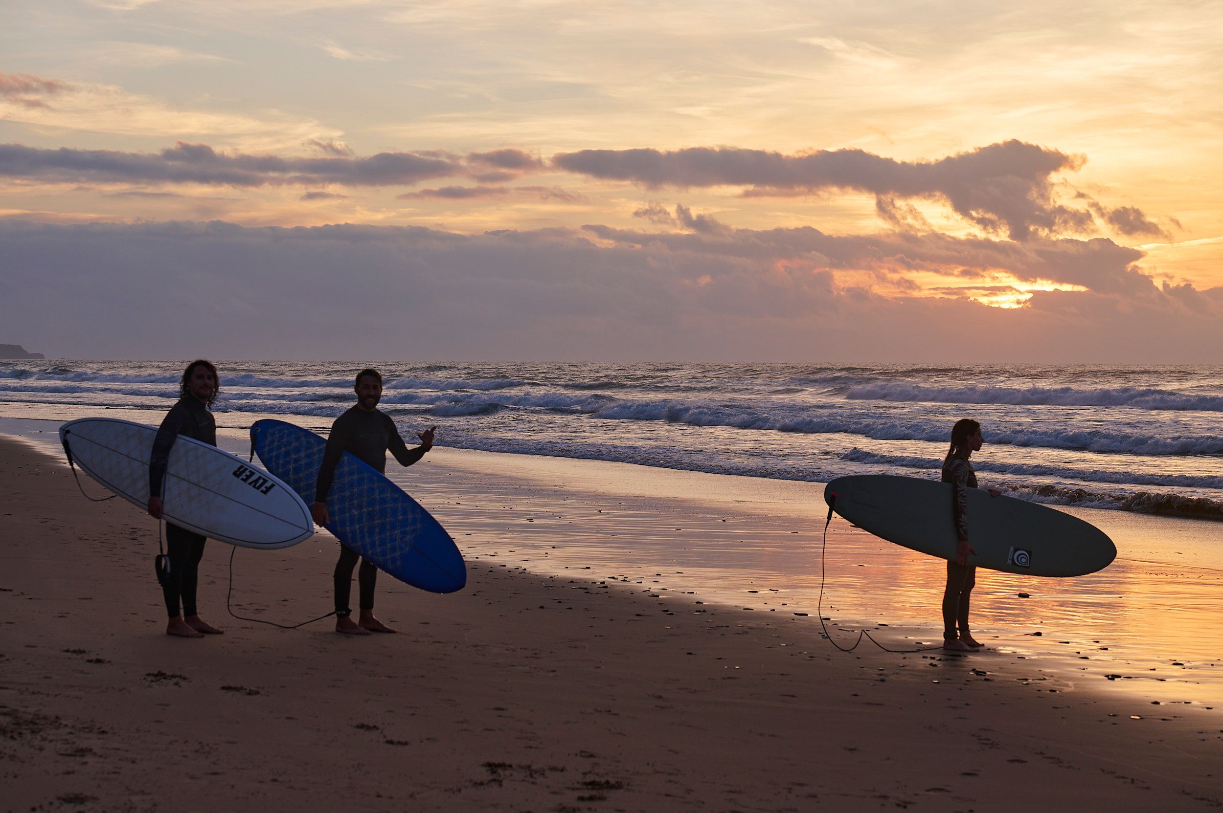 Surfers with Boards under Arms Standing on Beach at Dusk · Free Stock Photo