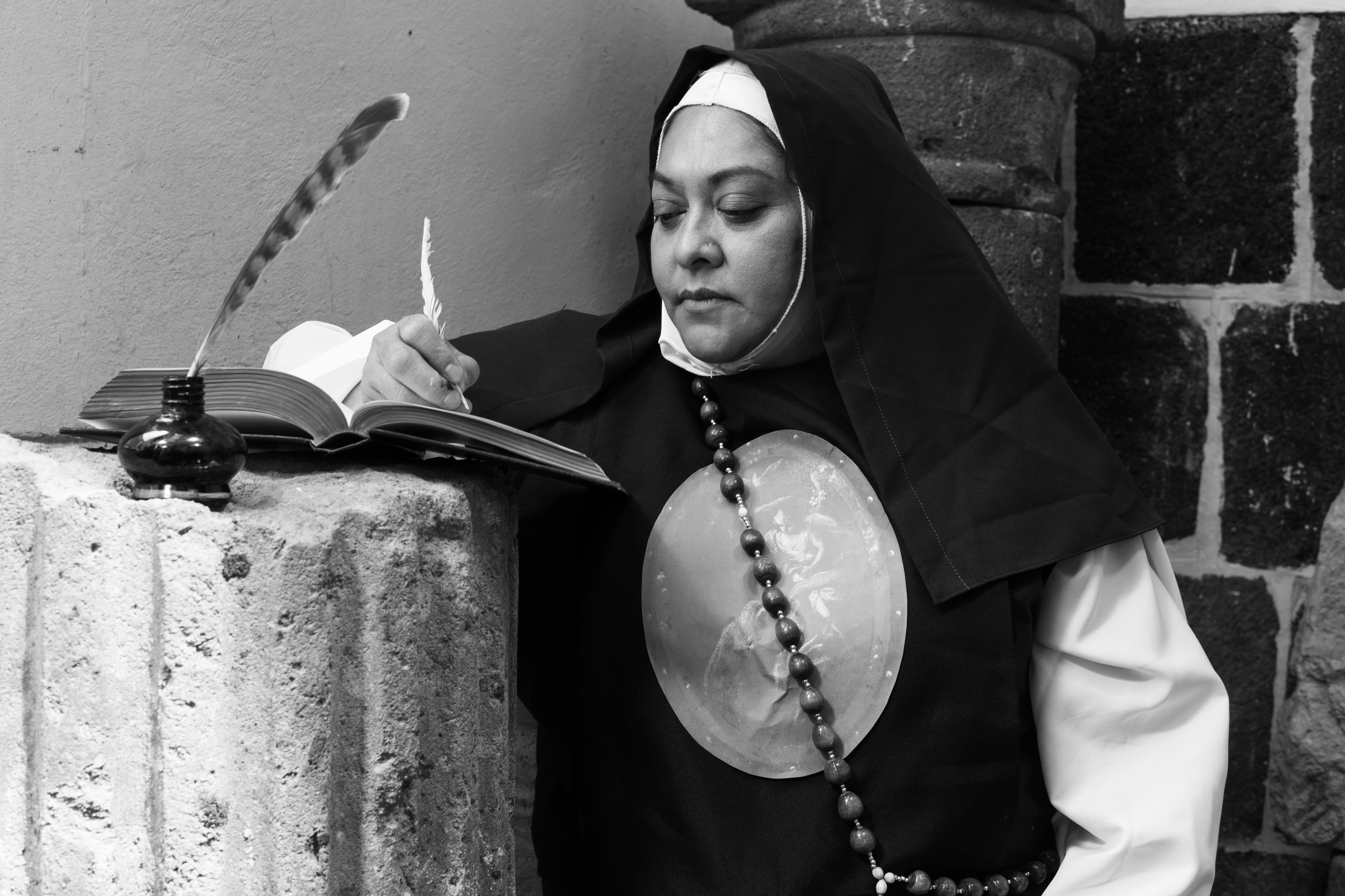 A nun is reading a book while sitting on a stone · Free Stock Photo