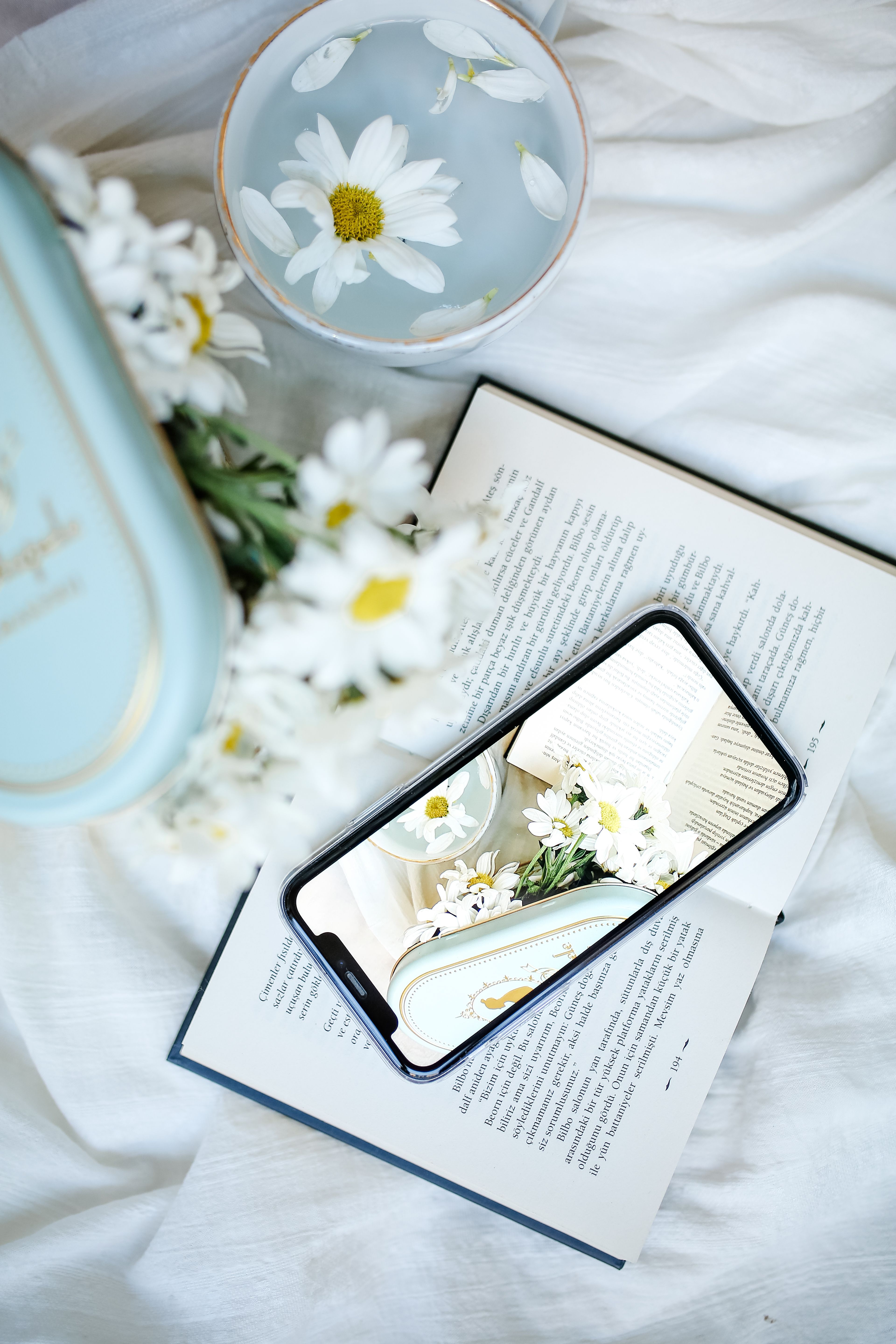 Close-up of a Smartphone Lying on an Open Book next to Flowers · Free ...