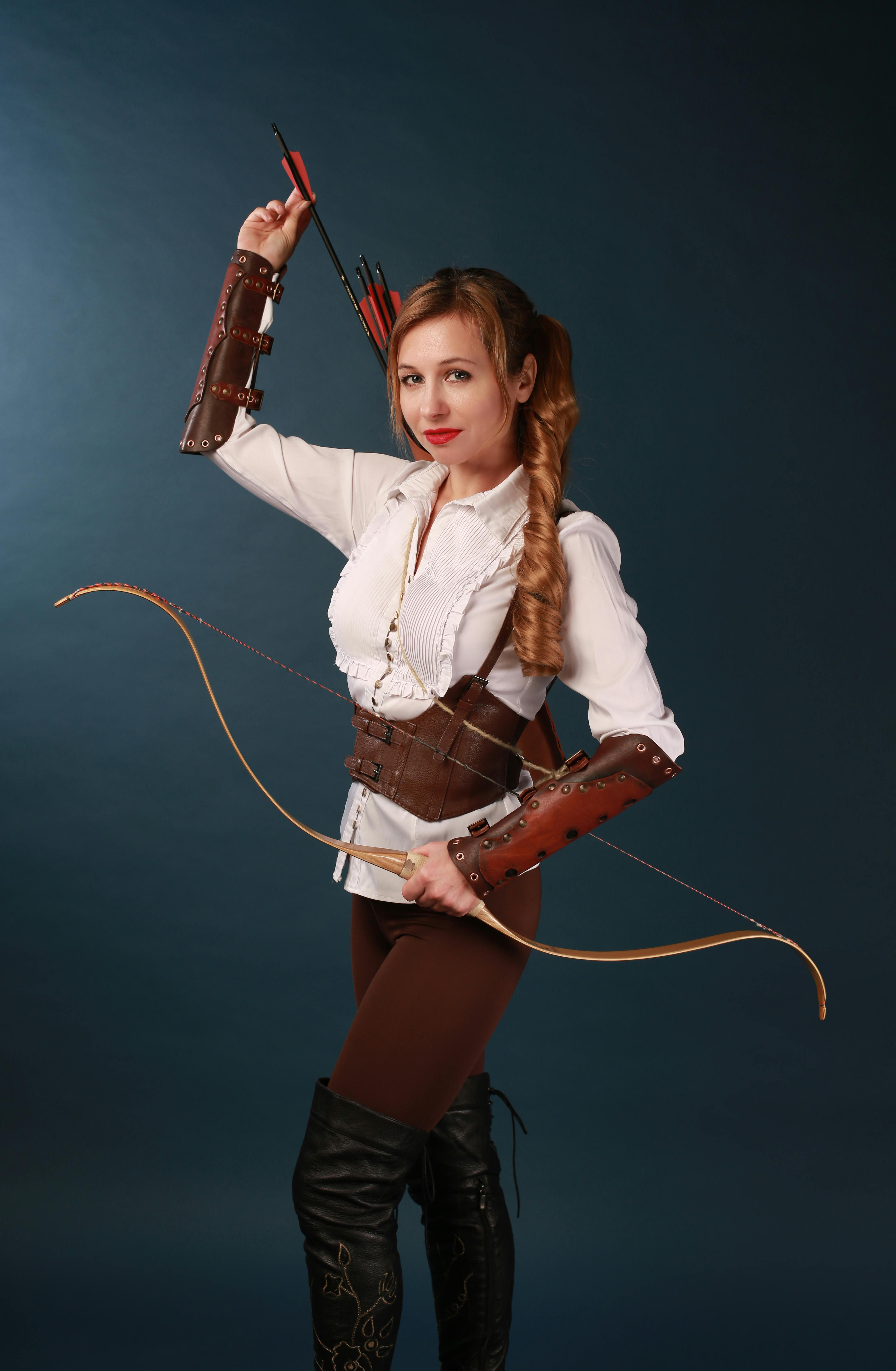 A woman in a costume holding a bow and arrow · Free Stock Photo