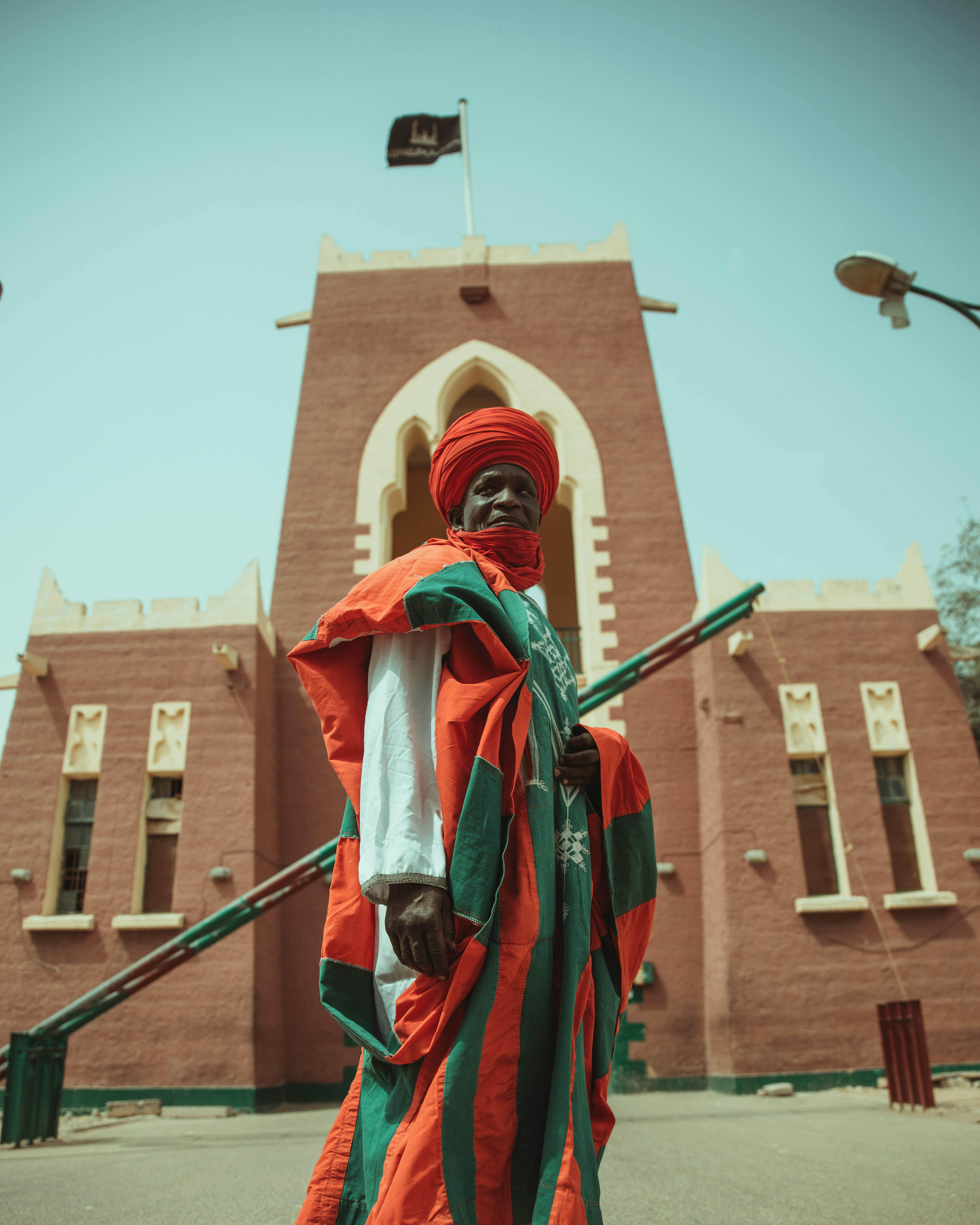 Man in Red and Green Traditional Gown Standing on Street by Gidan Rumfa ...