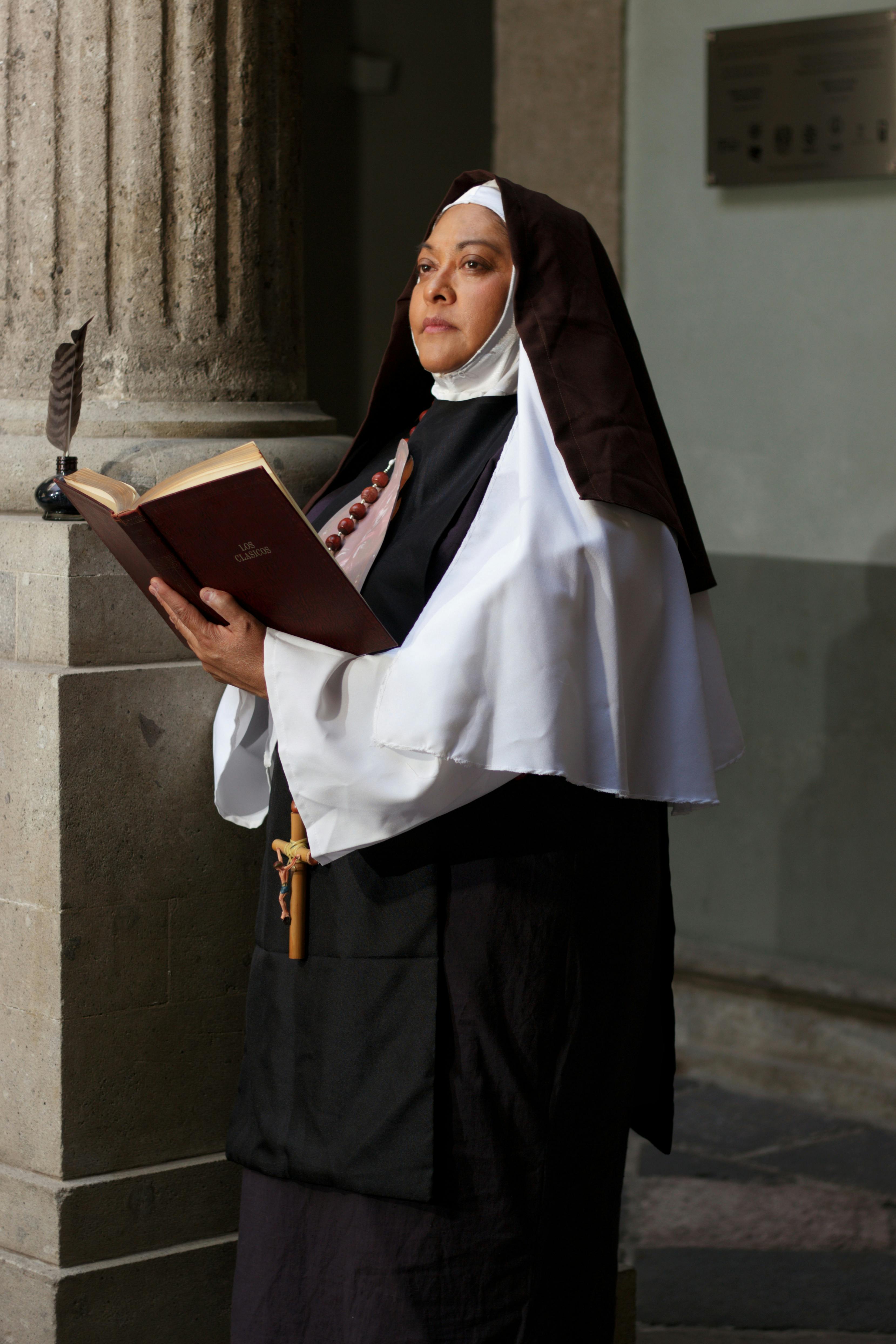 A nun reading a book in front of a pillar · Free Stock Photo