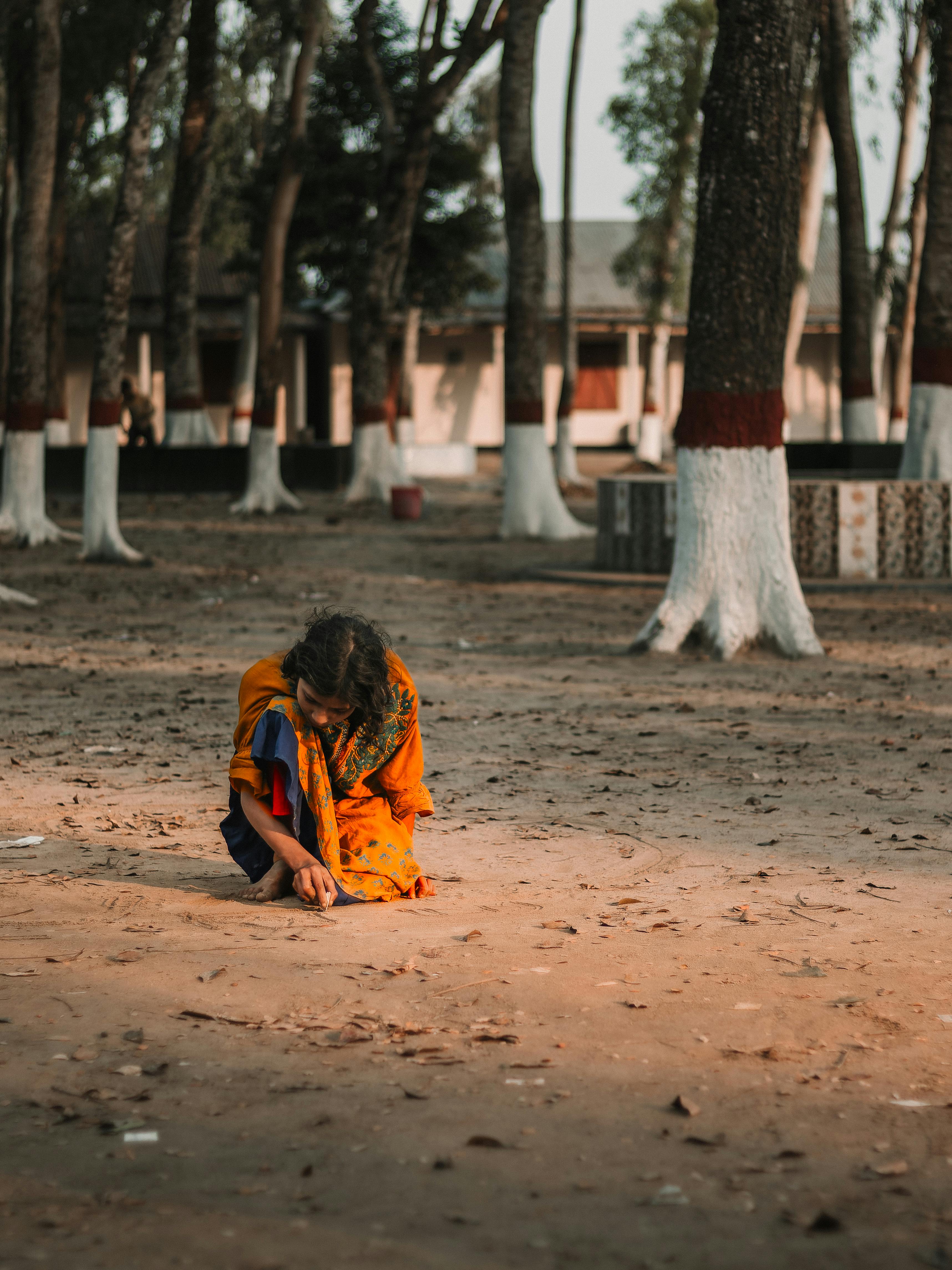 Crouching Girl Drawing in Dirt among Trees · Free Stock Photo