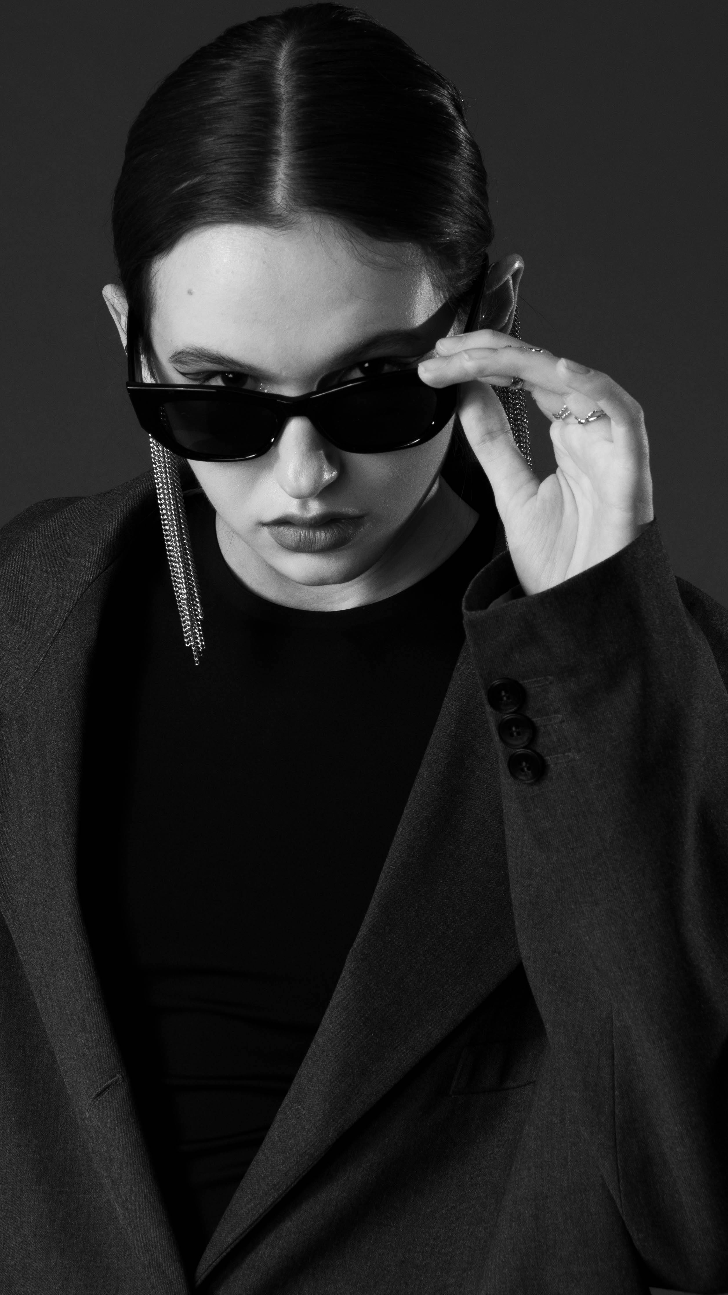 Elegantly Dressed Woman with a Dangling Earring Holding her Sunglasses ...