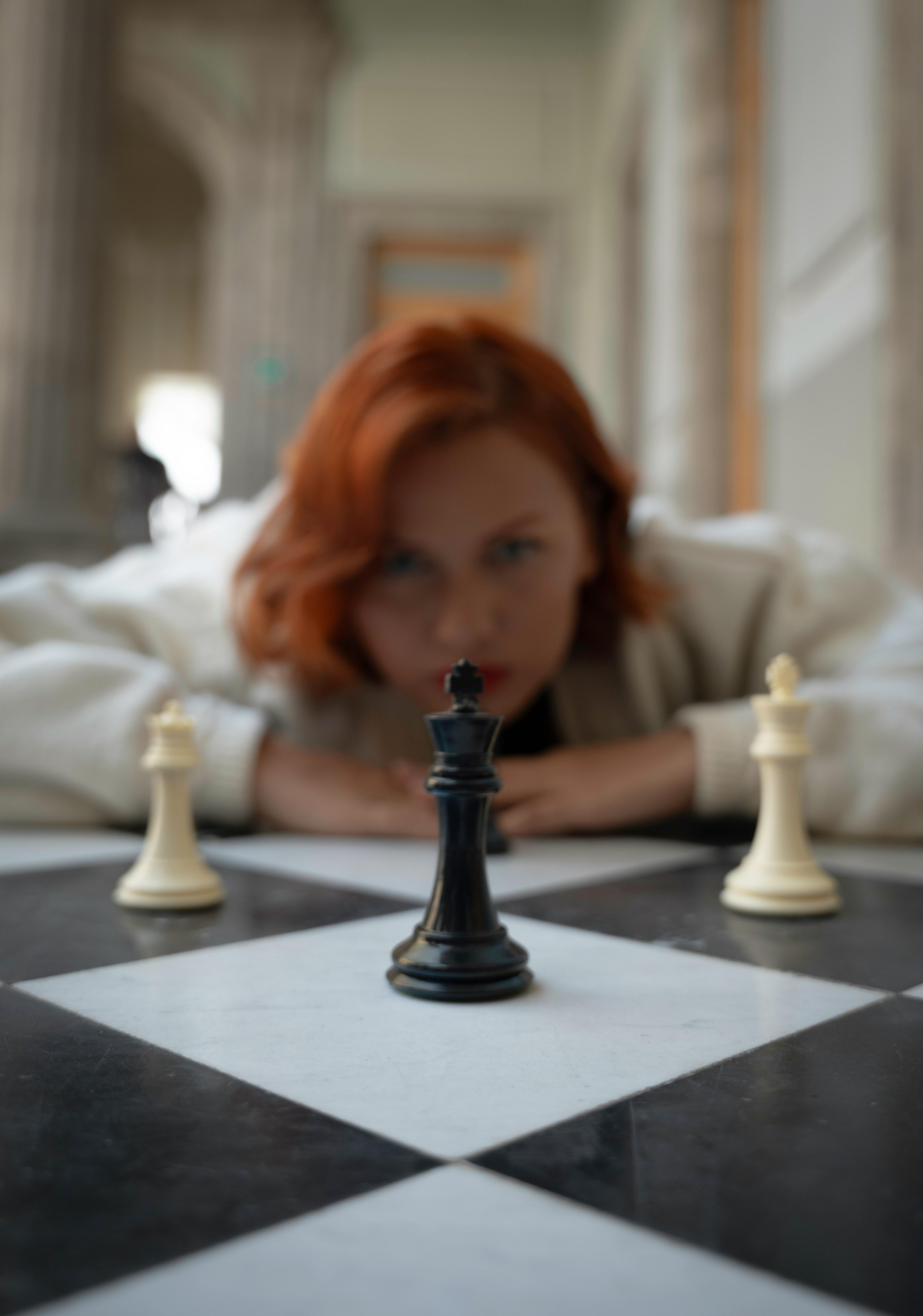 A woman with red hair laying on a chess board · Free Stock Photo