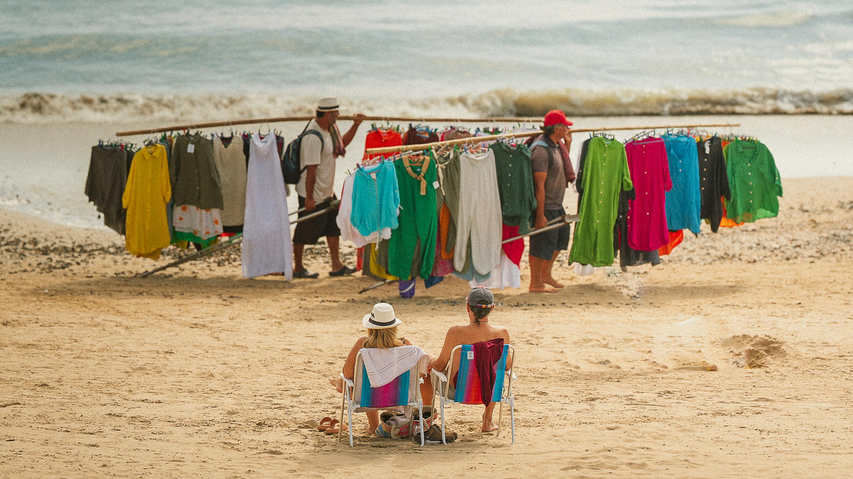 Men Carrying Clothes along Beach · Free Stock Photo