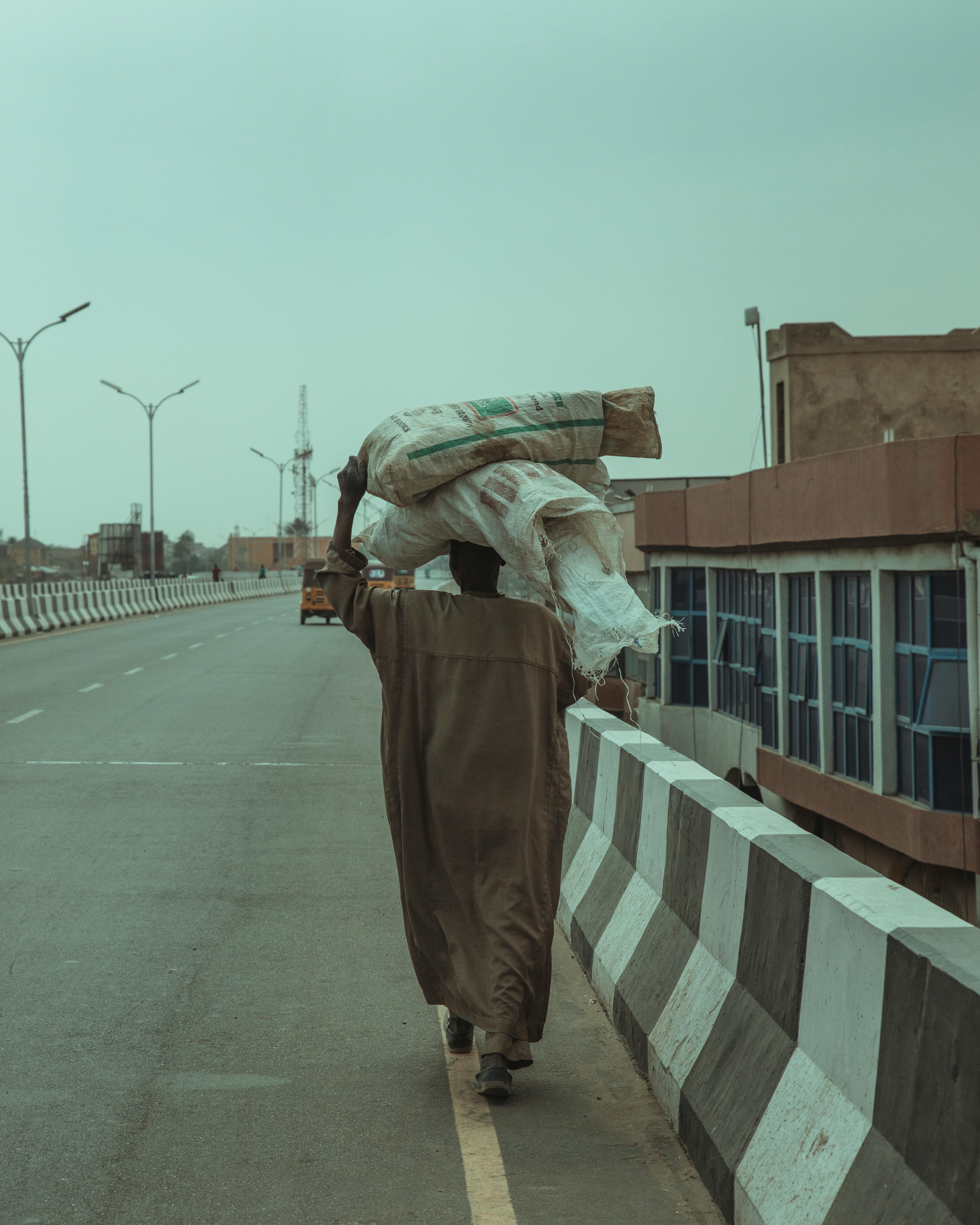 Man Carrying Bags on Head on Road · Free Stock Photo